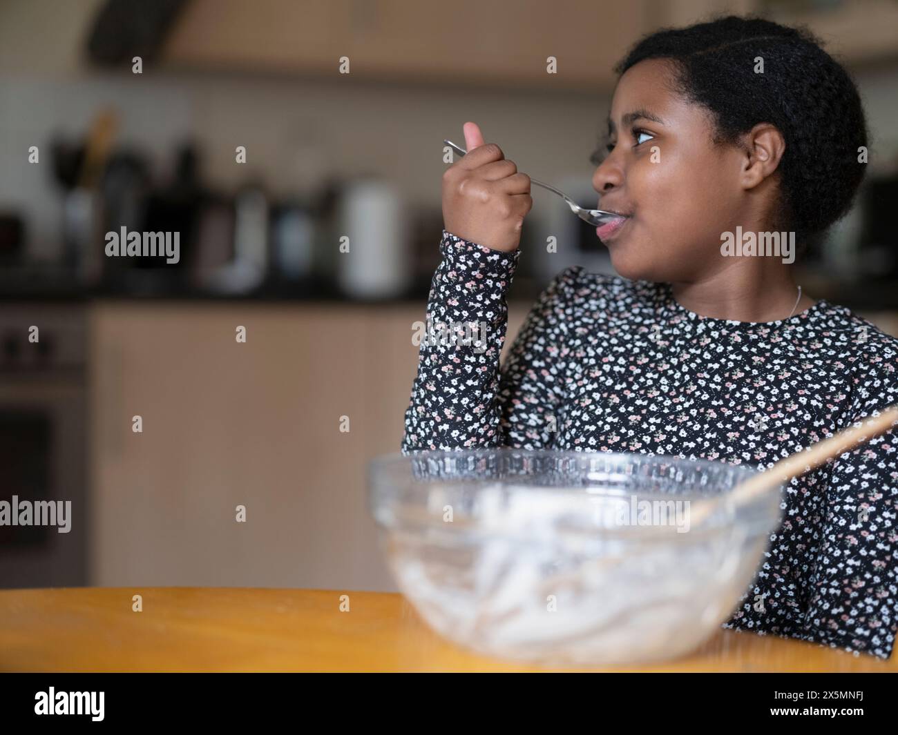 Girl eating cookie batter from bowl Stock Photo - Alamy