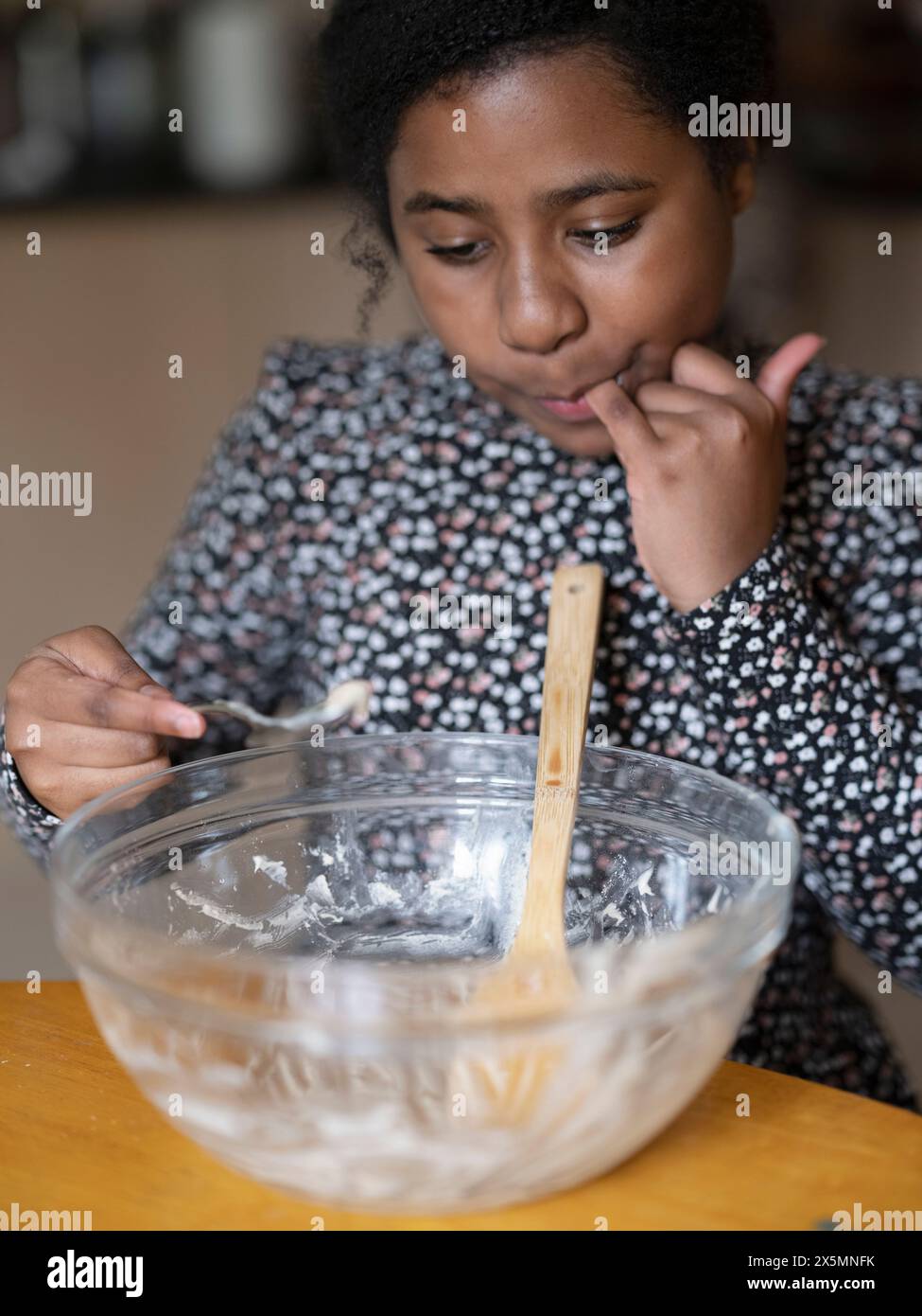 Girl eating cookie batter from bowl Stock Photo - Alamy
