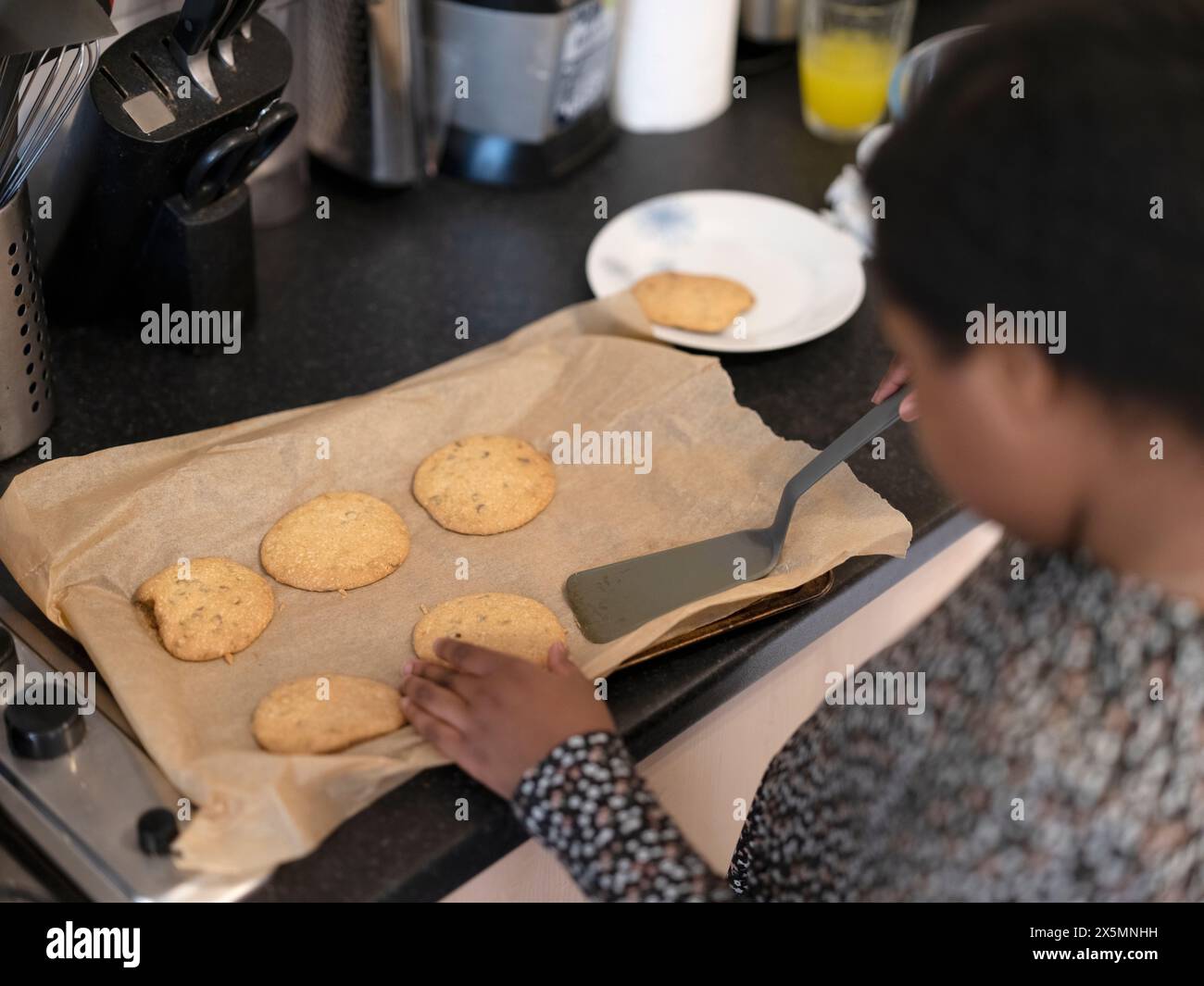 Girl taking cookies off baking sheet Stock Photo - Alamy
