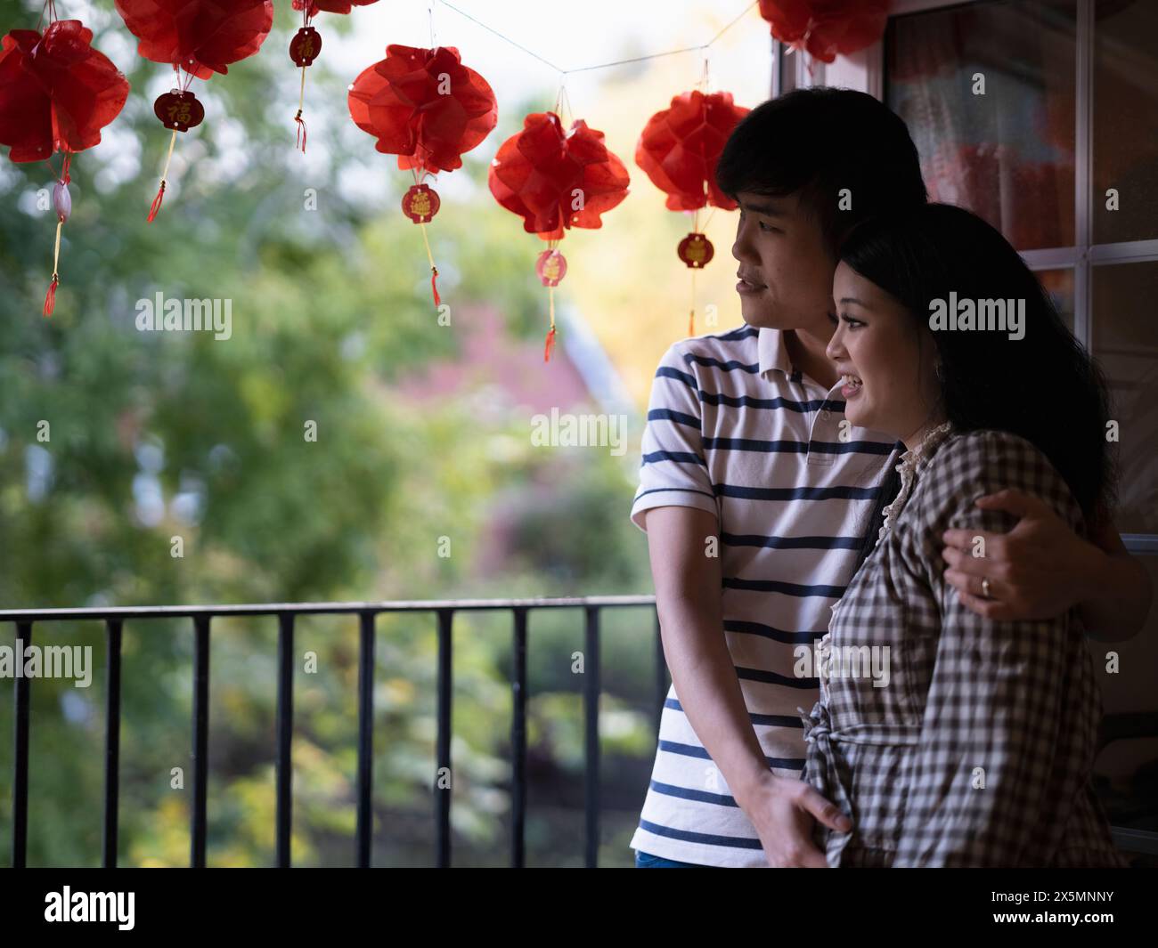 Couple hugging next to window with traditional Chinese decorations ...
