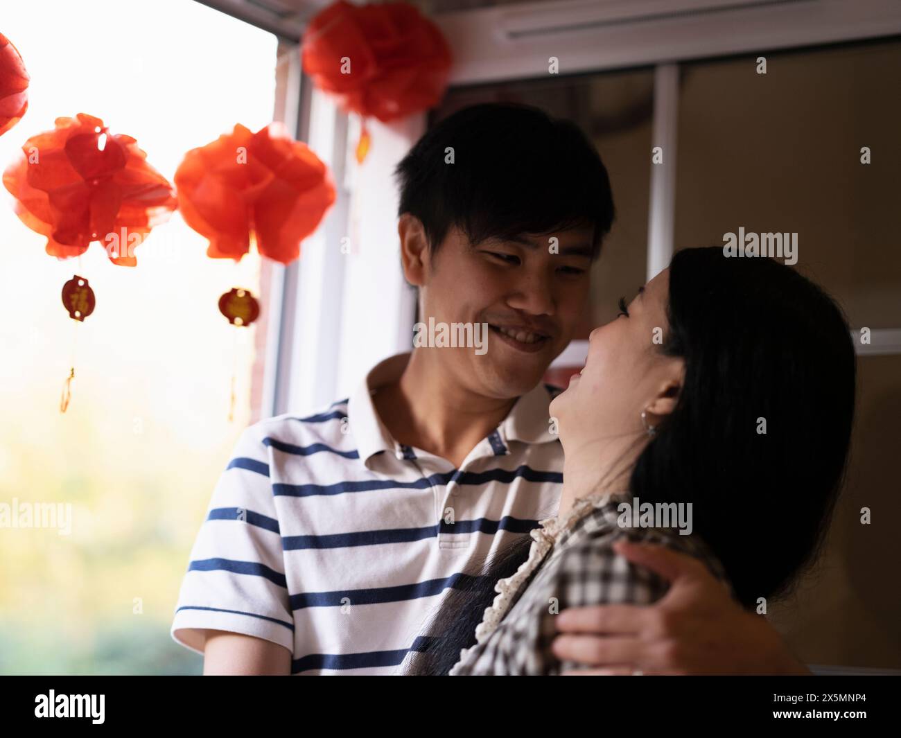 Couple hugging next to window with traditional Chinese decorations ...