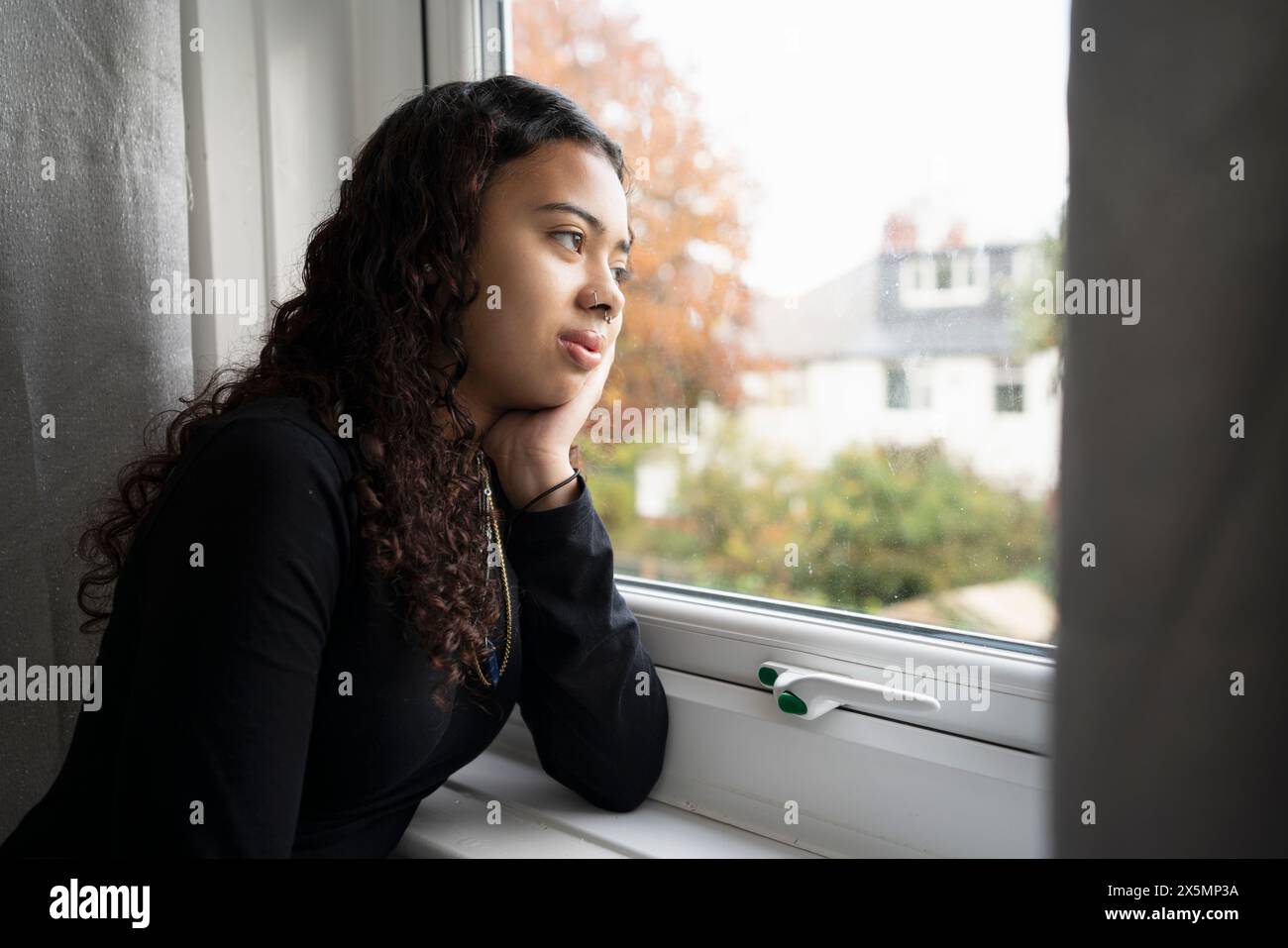 Thoughtful teenage girl looking through window Stock Photo - Alamy