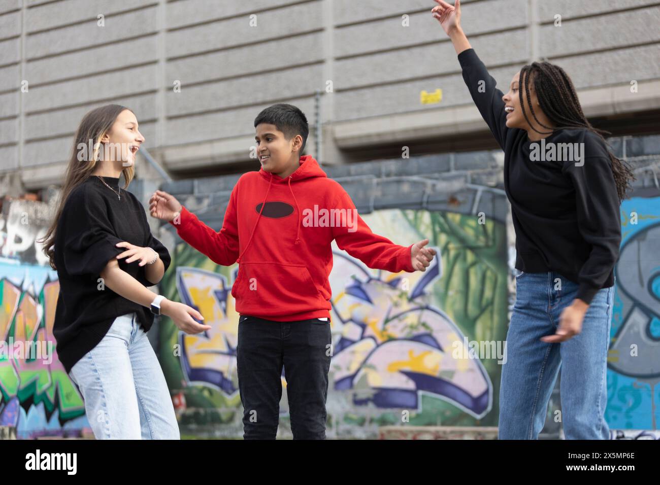 Smiling friends laughing by graffiti wall Stock Photo - Alamy