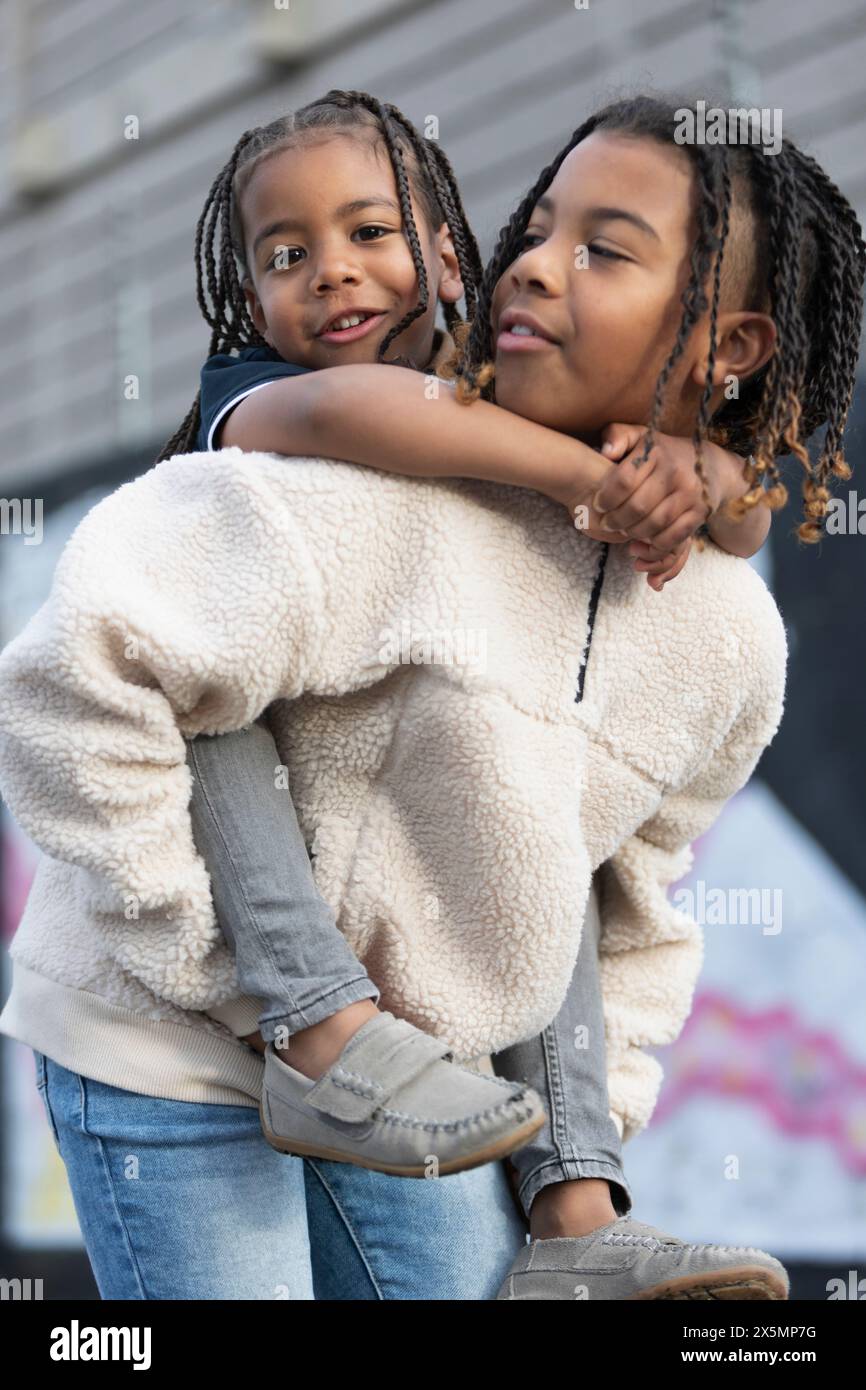 Portrait of boy giving piggyback ride to younger brother Stock Photo ...