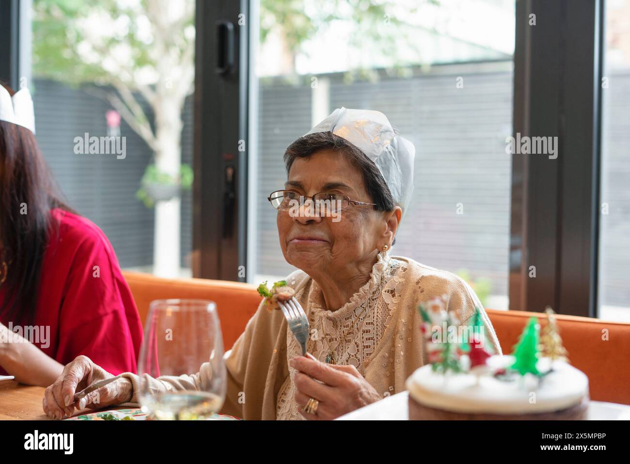 Senior woman wearing paper crown enjoying Christmas dinner Stock Photo ...