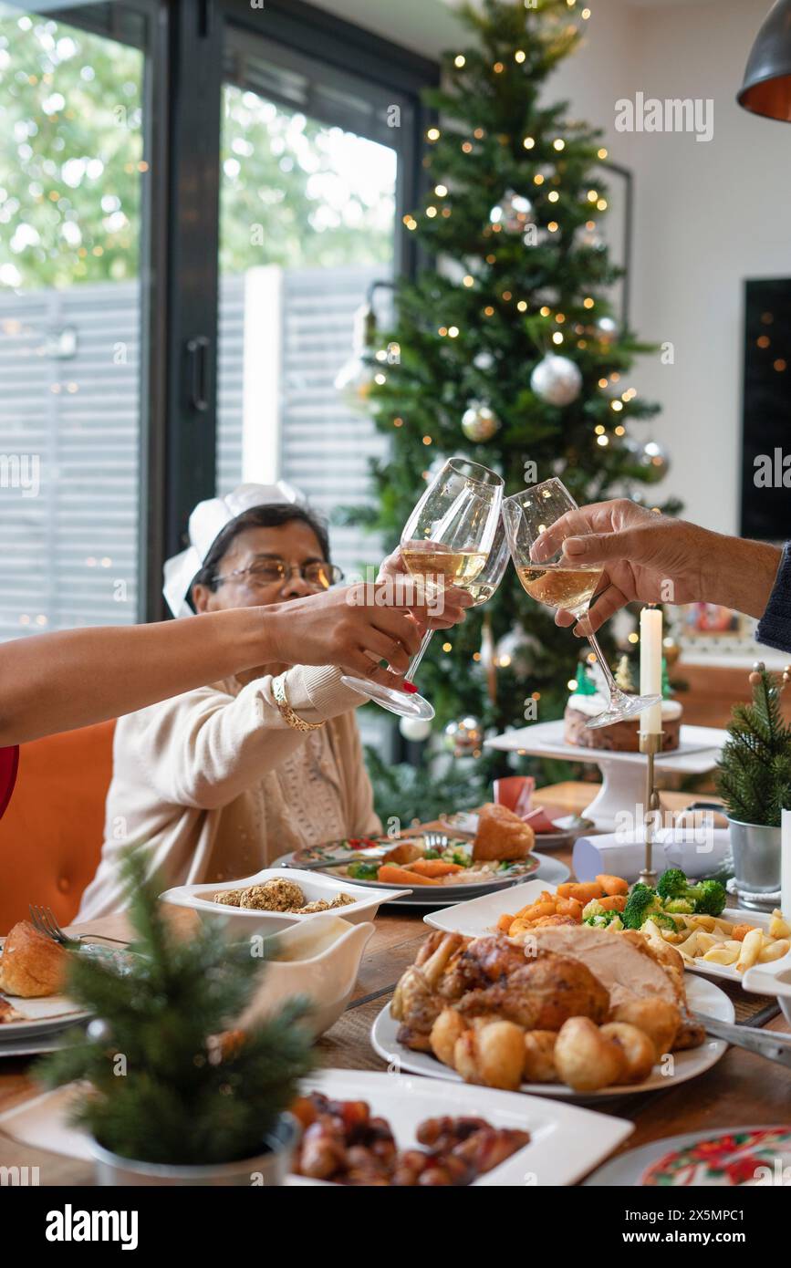 Family wearing paper crowns toasting during Christmas dinner Stock ...