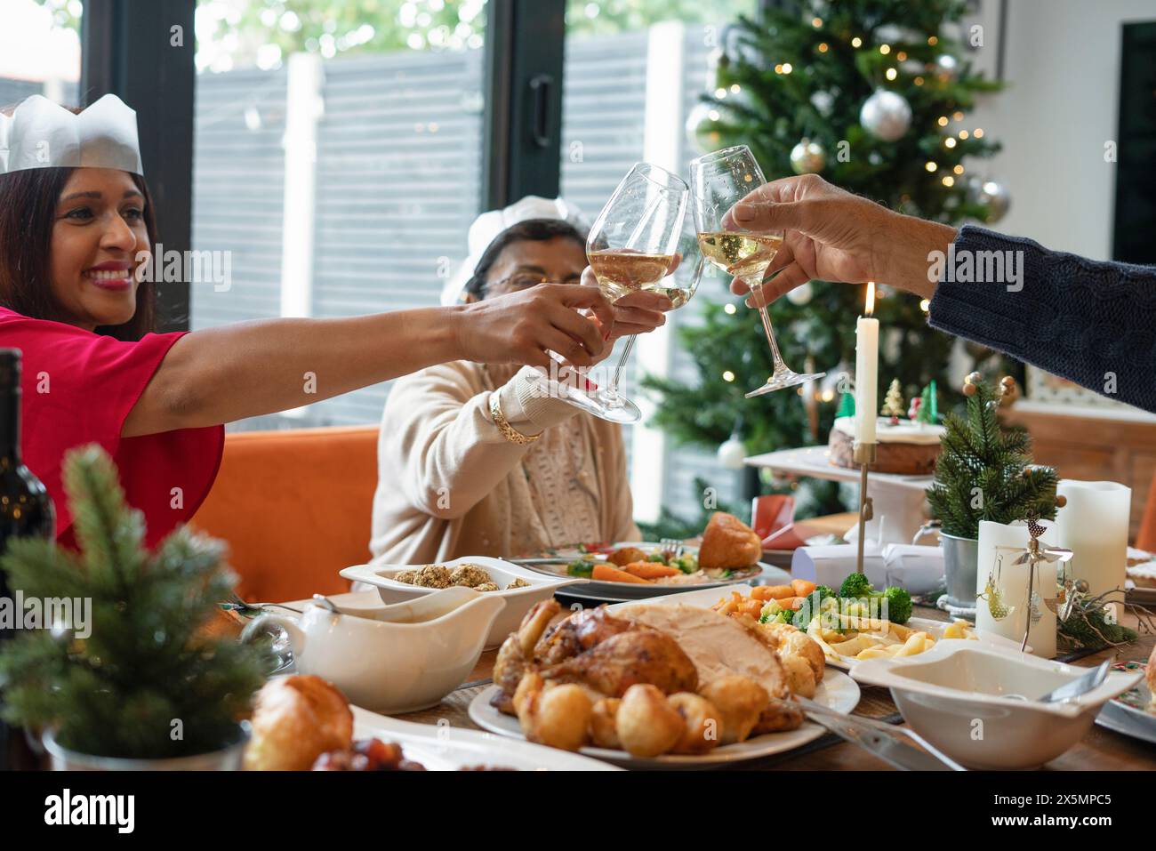 Family wearing paper crowns toasting during Christmas dinner Stock ...