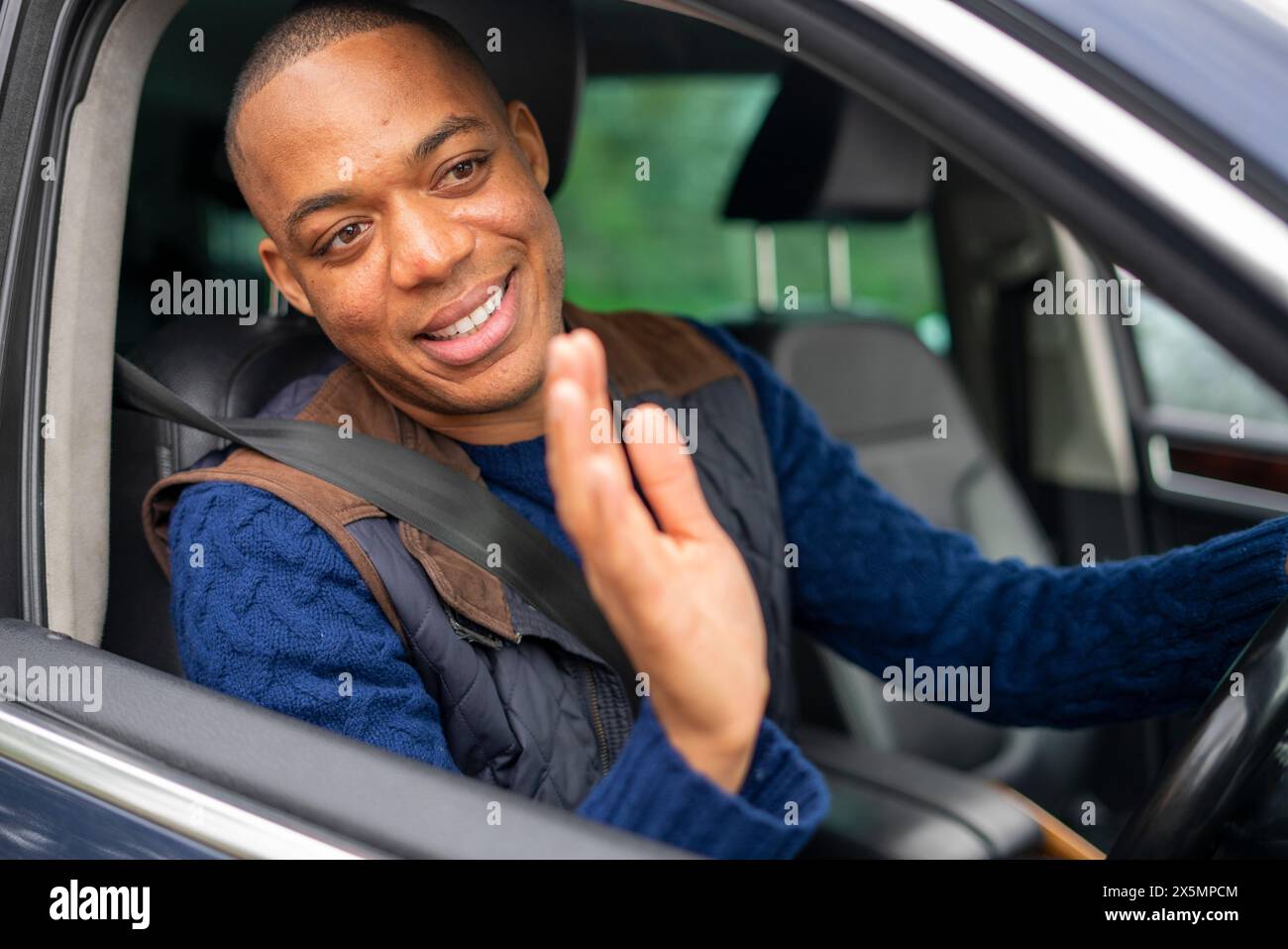 Smiling man sitting in car and waving through window Stock Photo - Alamy