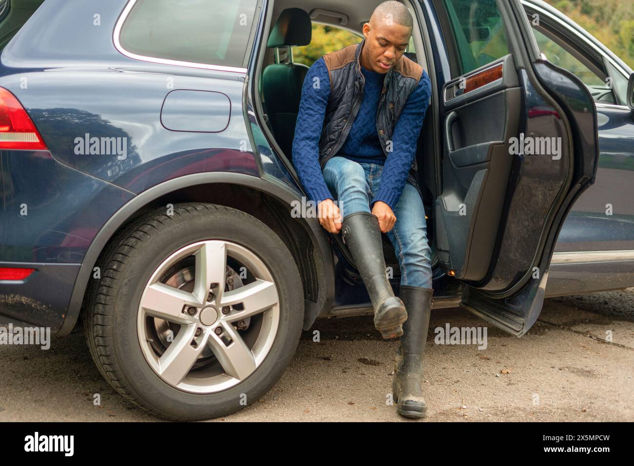 Man sitting on a back seat of car and putting on rubber boots Stock ...