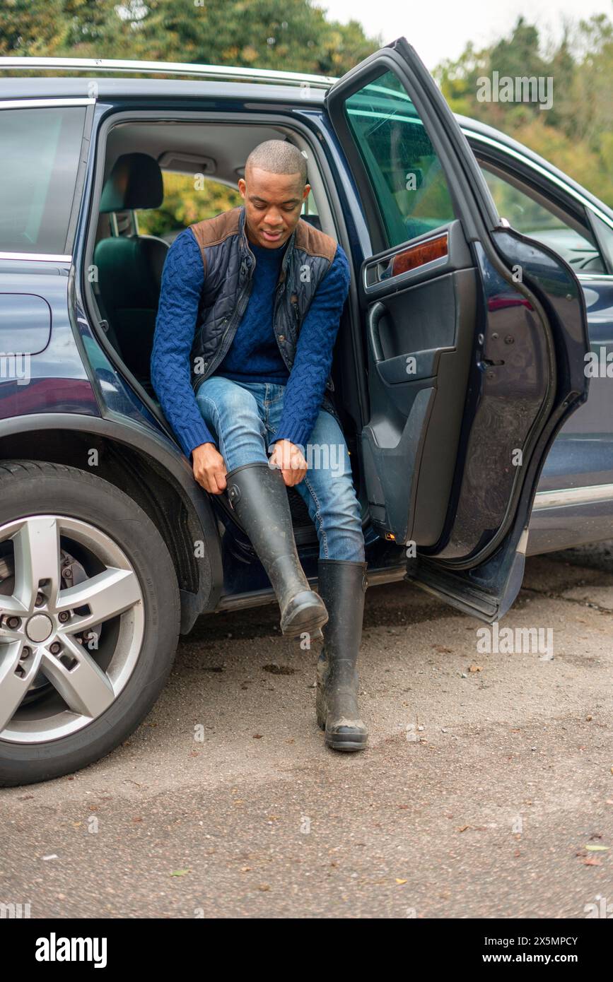 Man putting on rubber boots at cars back seat Stock Photo - Alamy