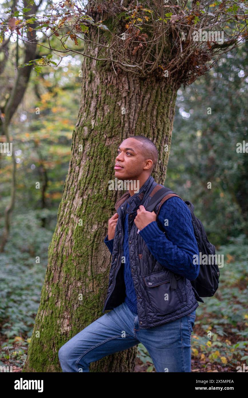 Man standing next to tree and looking at view during hike Stock Photo ...