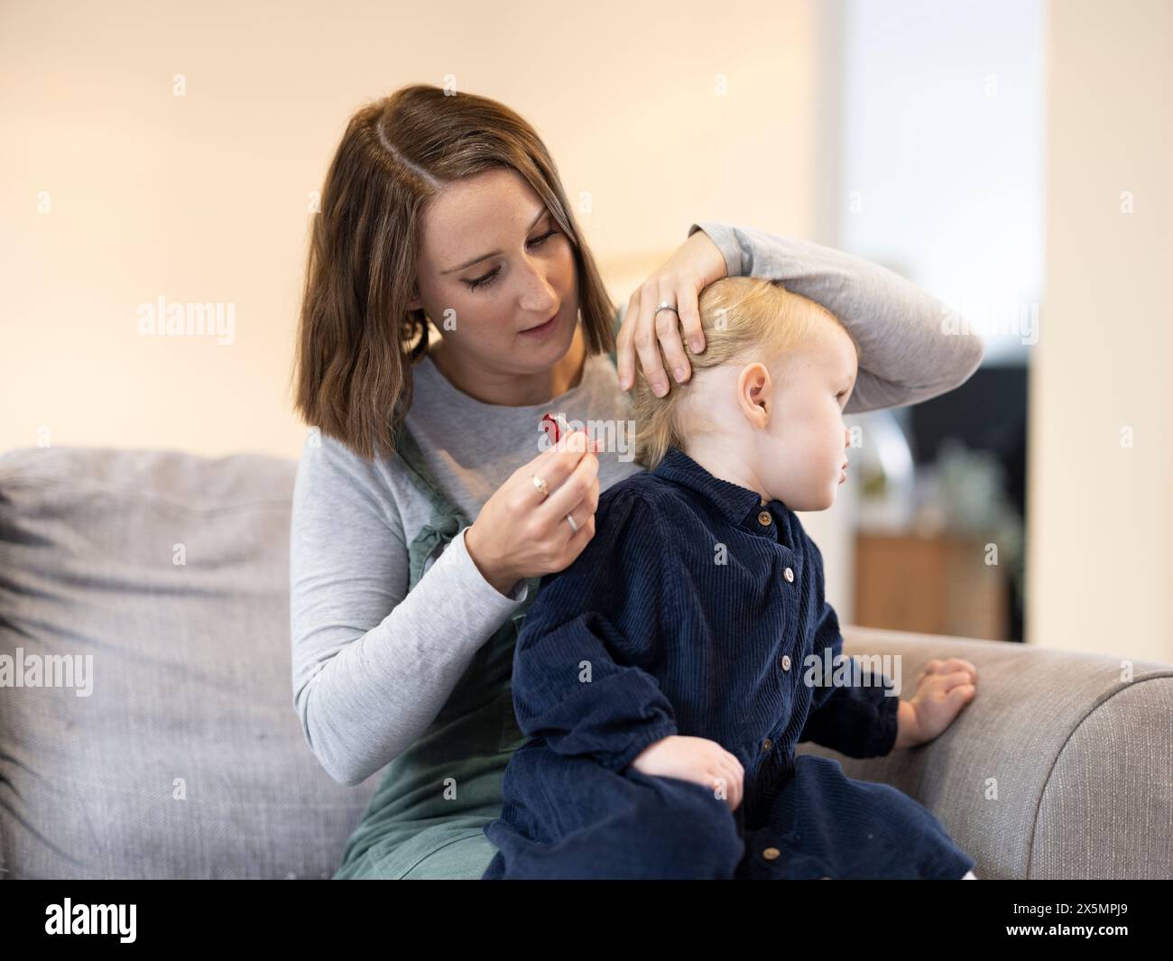 Mother putting hearing aid in daughters ear Stock Photo - Alamy