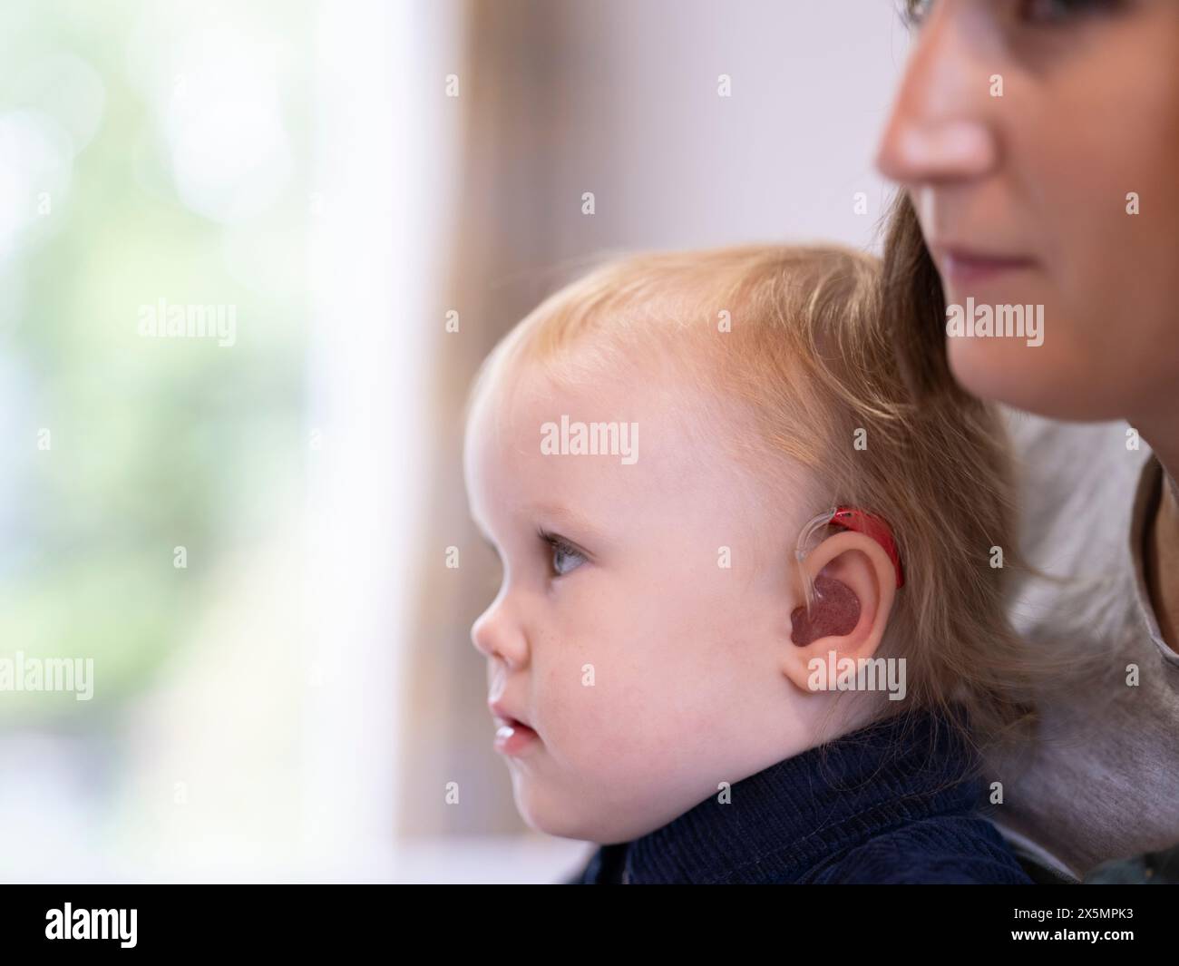 Mother holding daughter wearing hearing aid Stock Photo - Alamy