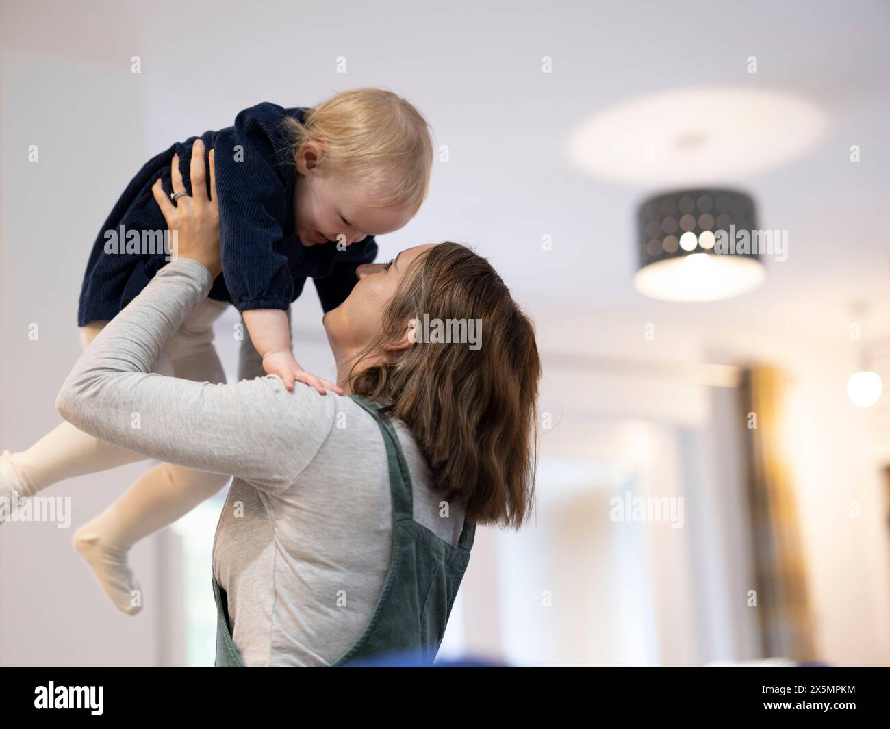 Mother lifting daughter at home Stock Photo - Alamy
