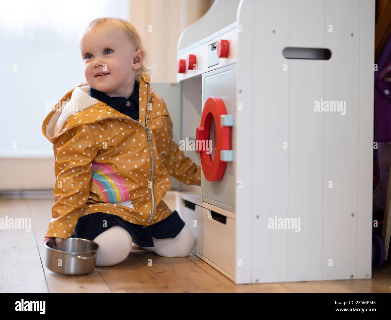 Girl wearing raincoat playing with toy kitchen at home Stock Photo - Alamy