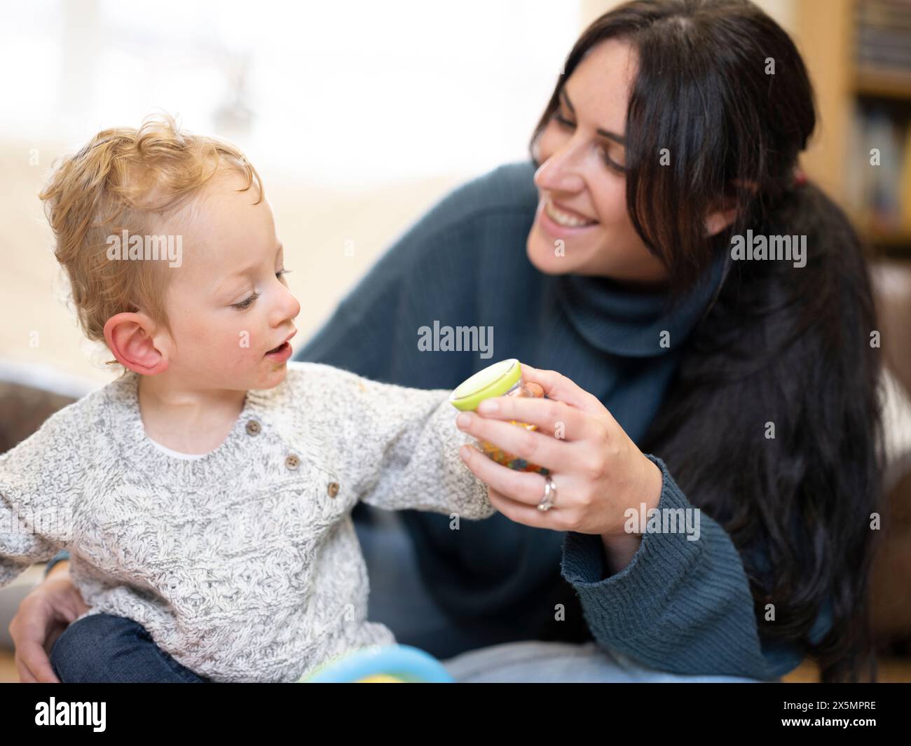 Mother and son holding toy rattle together Stock Photo - Alamy