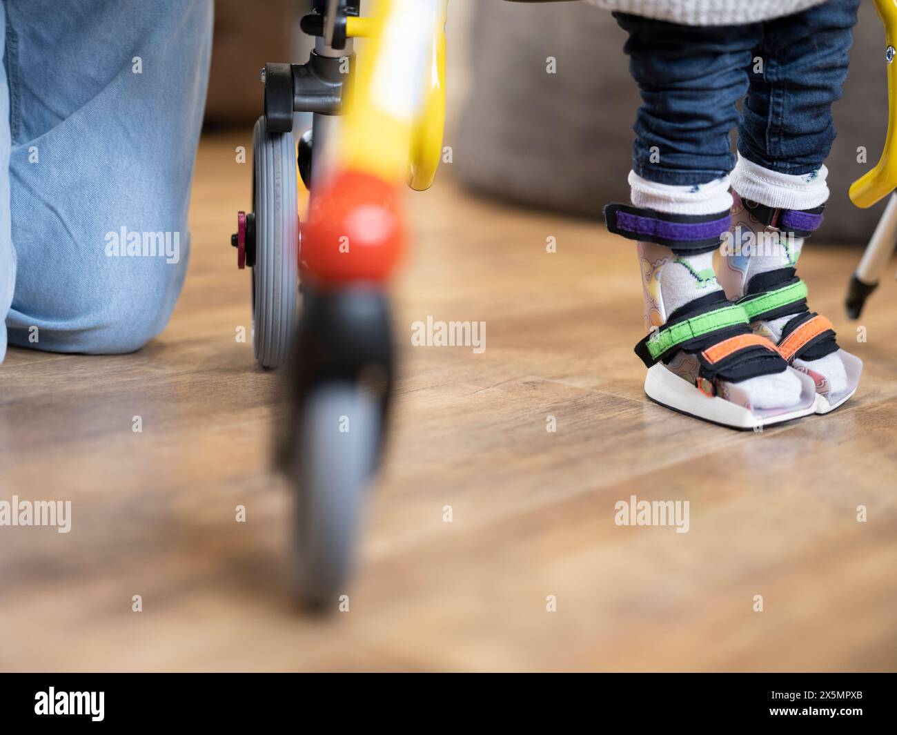 Mother kneeling next to son wearing leg braces Stock Photo - Alamy