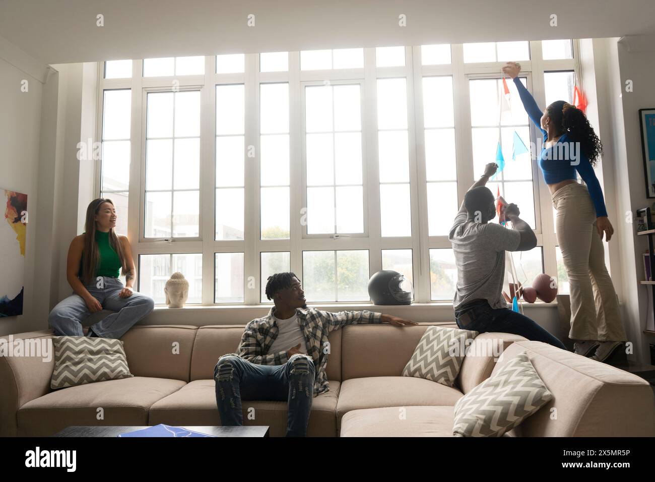 Friends decorating window with pennant flags Stock Photo - Alamy