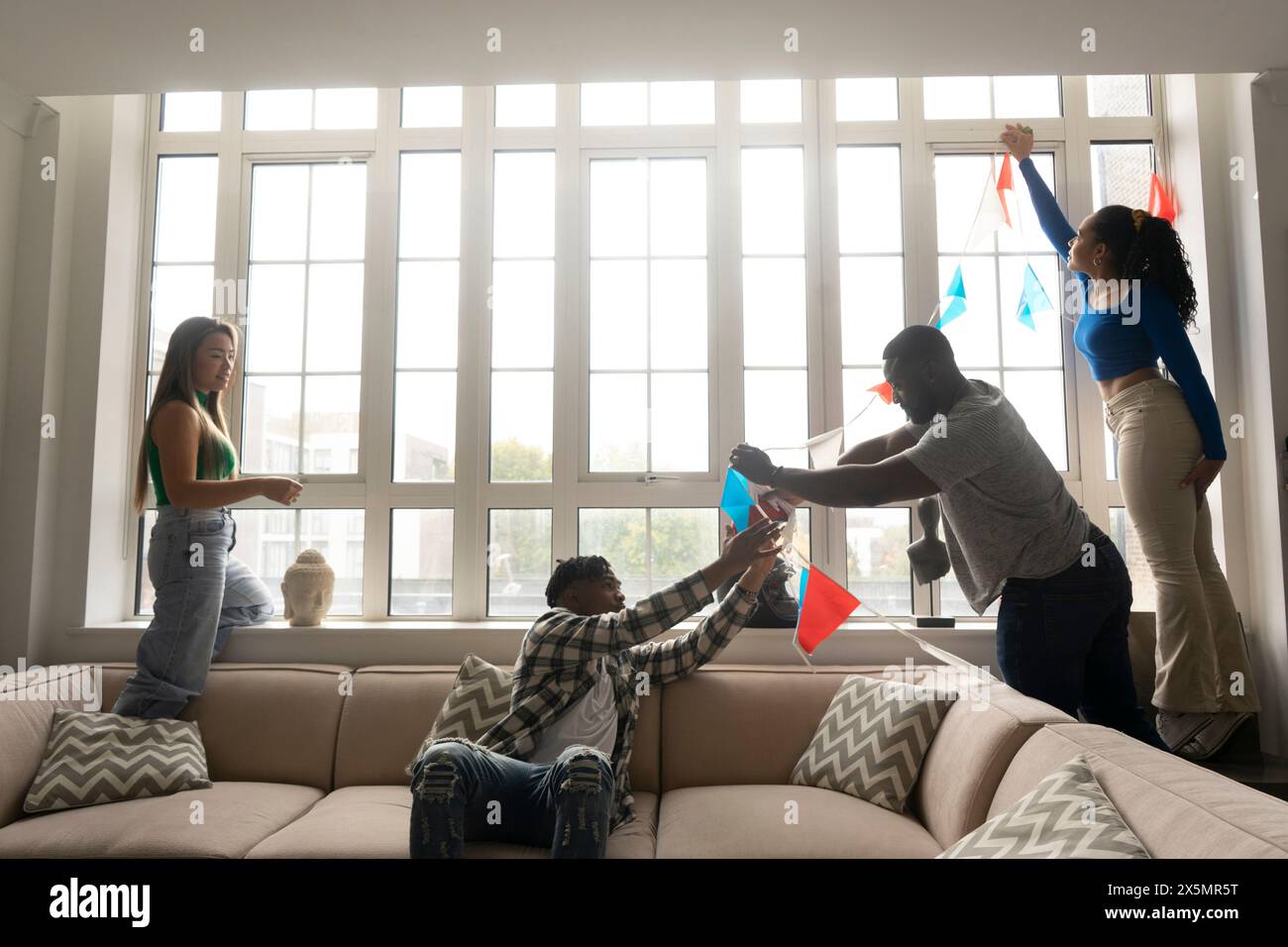 Friends decorating window with pennant flags Stock Photo - Alamy
