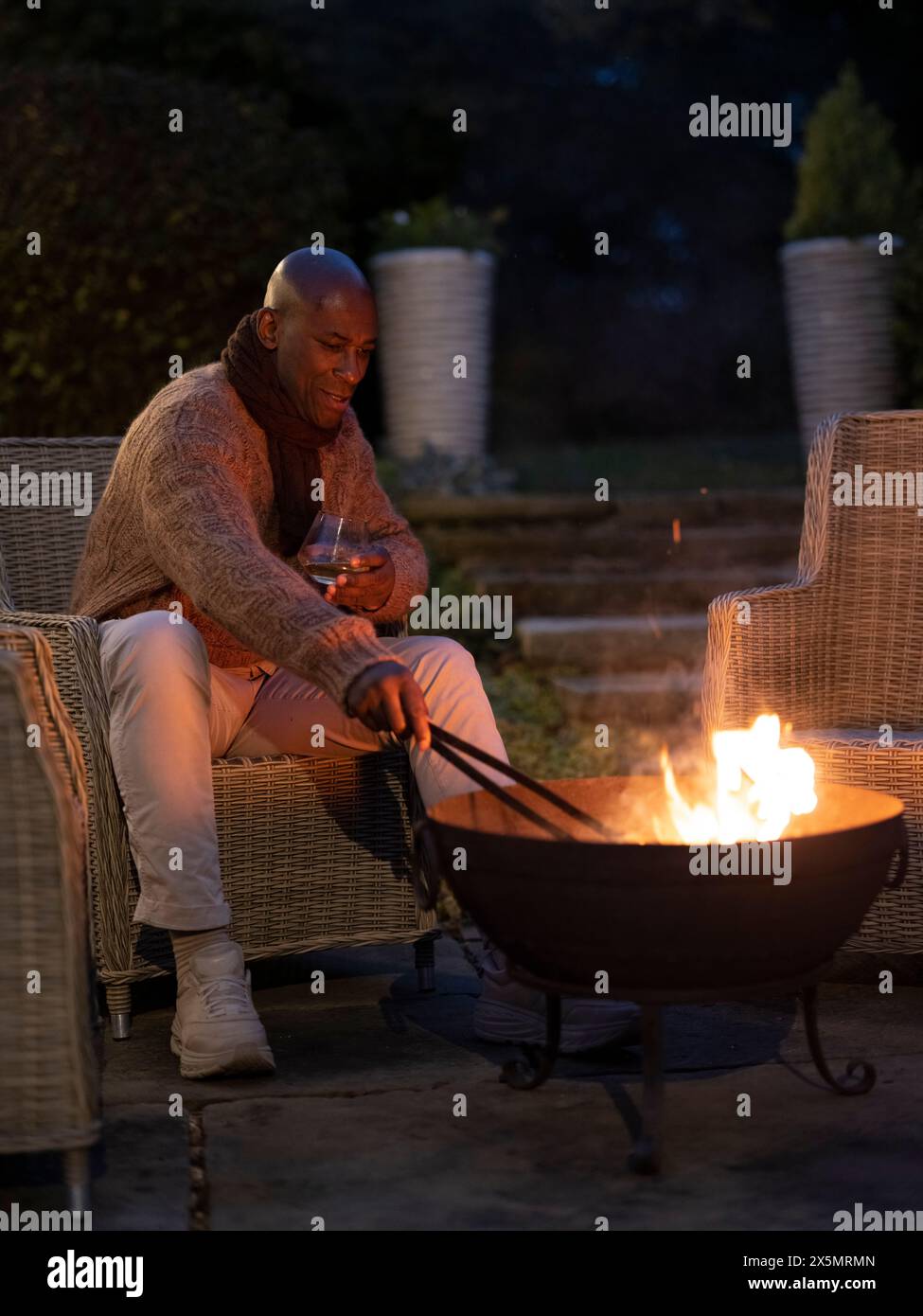 Man sitting by fire pit on patio Stock Photo - Alamy