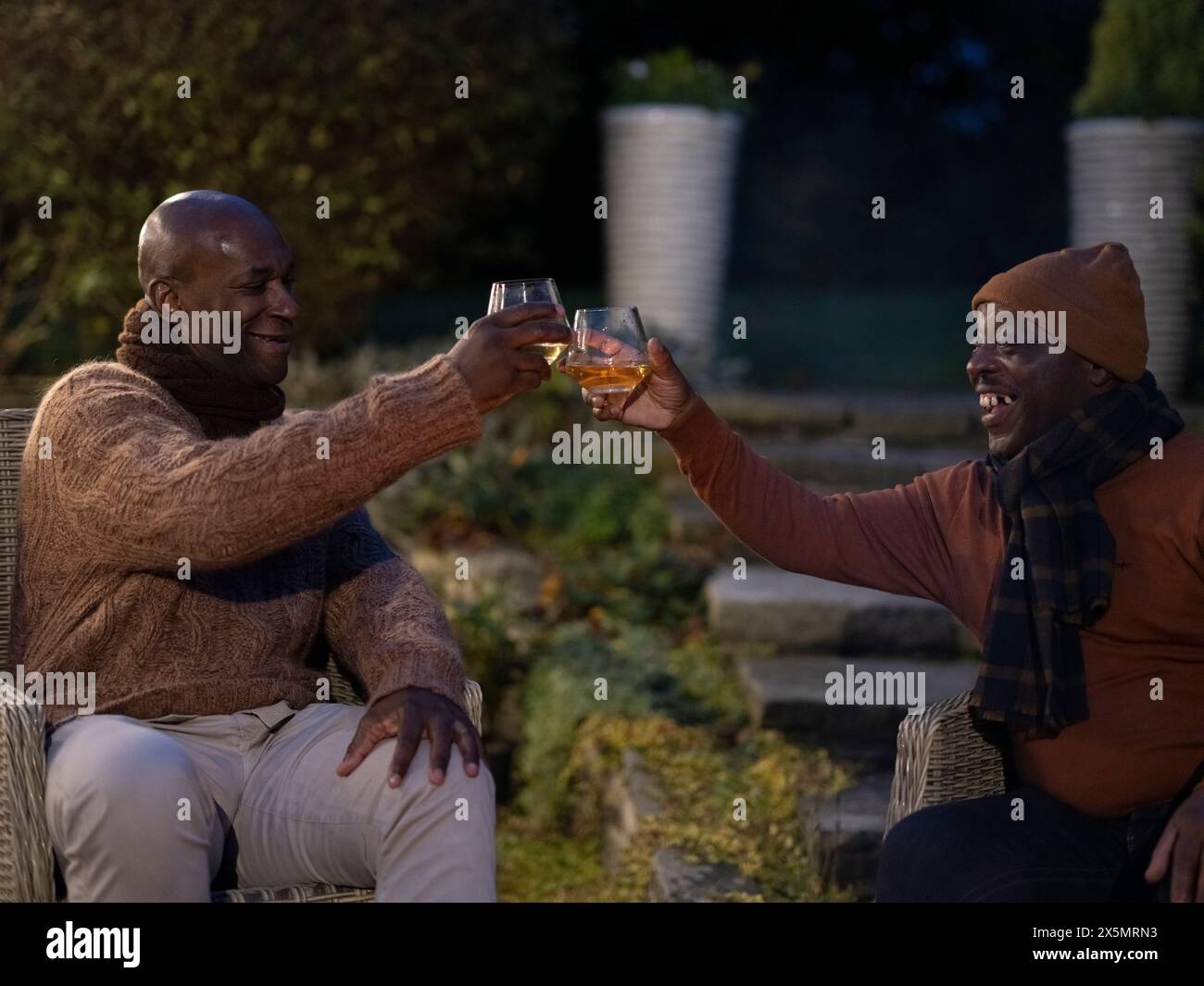 Men sitting on patio and raising toast Stock Photo - Alamy