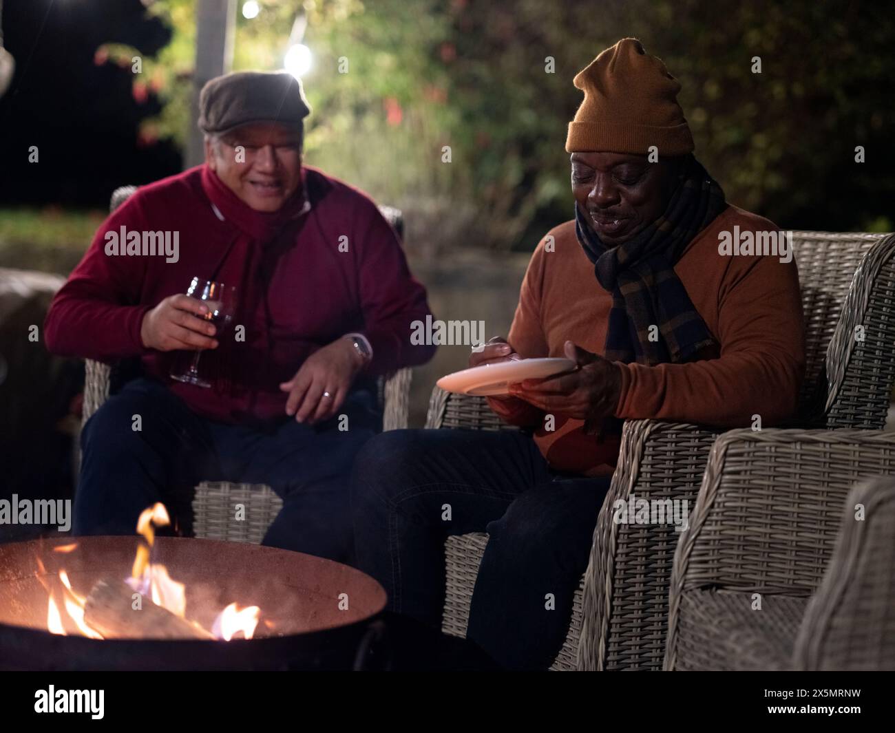 Male friends relaxing by fire pit Stock Photo - Alamy