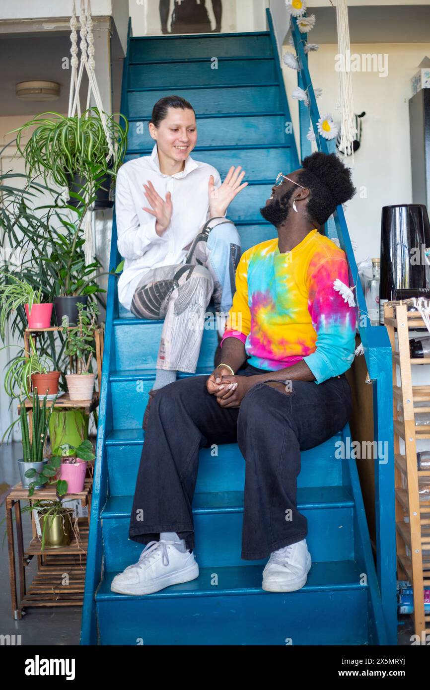 Friends sitting on steps and talking Stock Photo - Alamy