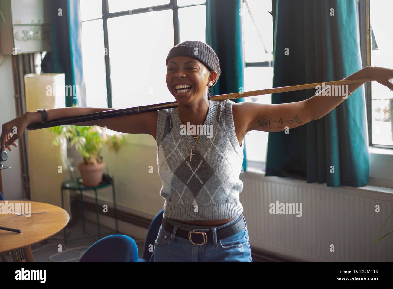 Laughing young woman holding pool cue at home Stock Photo - Alamy