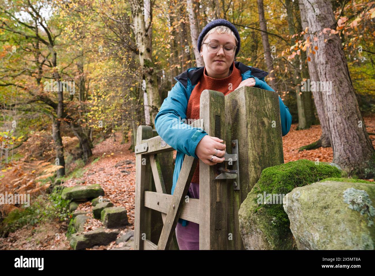 Female hiker opening gate in forest Stock Photo - Alamy