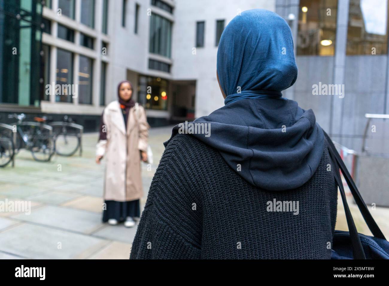 Two women wearing hijabs meeting in street Stock Photo - Alamy