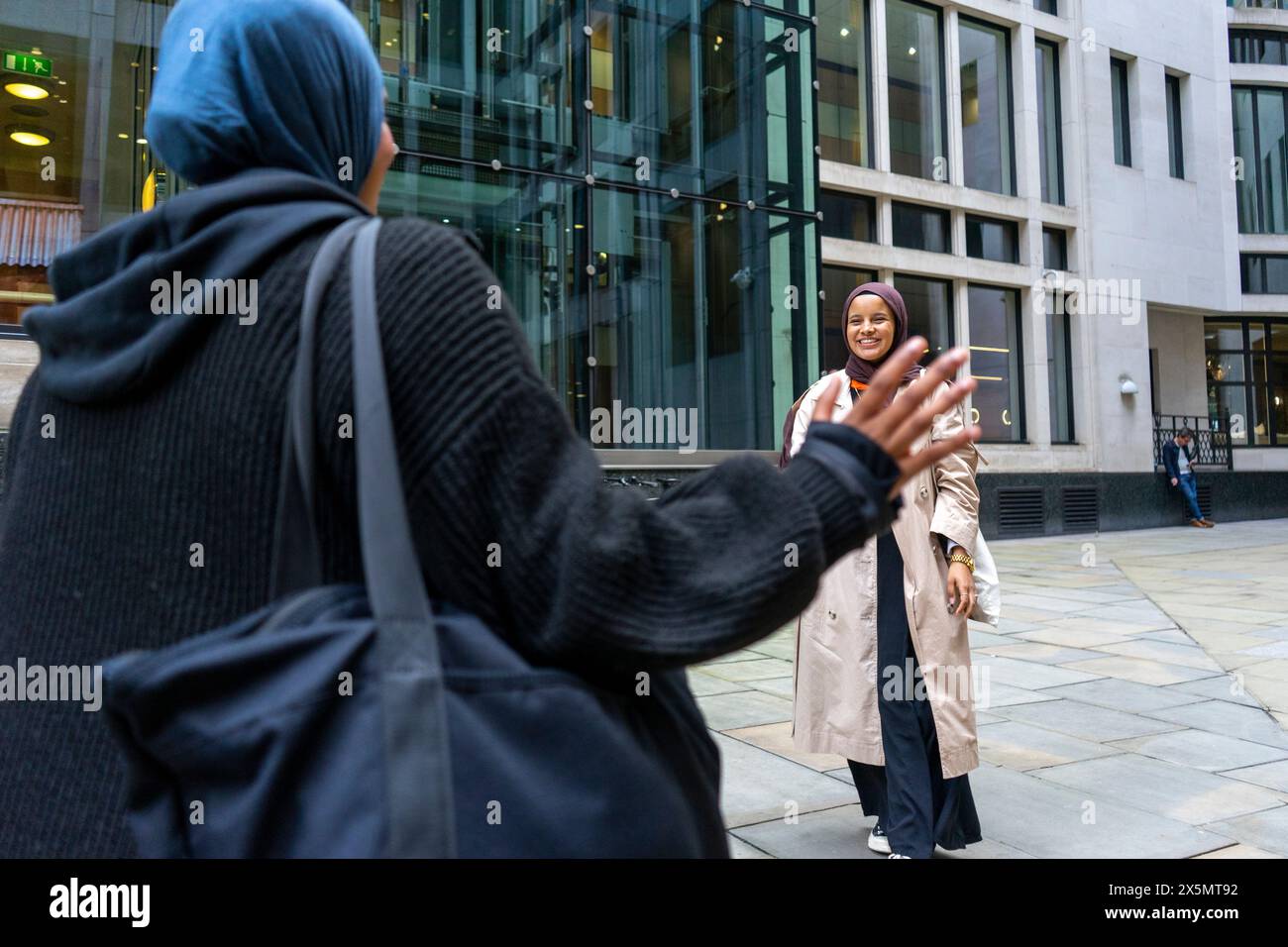 Two women wearing hijabs meeting in street Stock Photo - Alamy