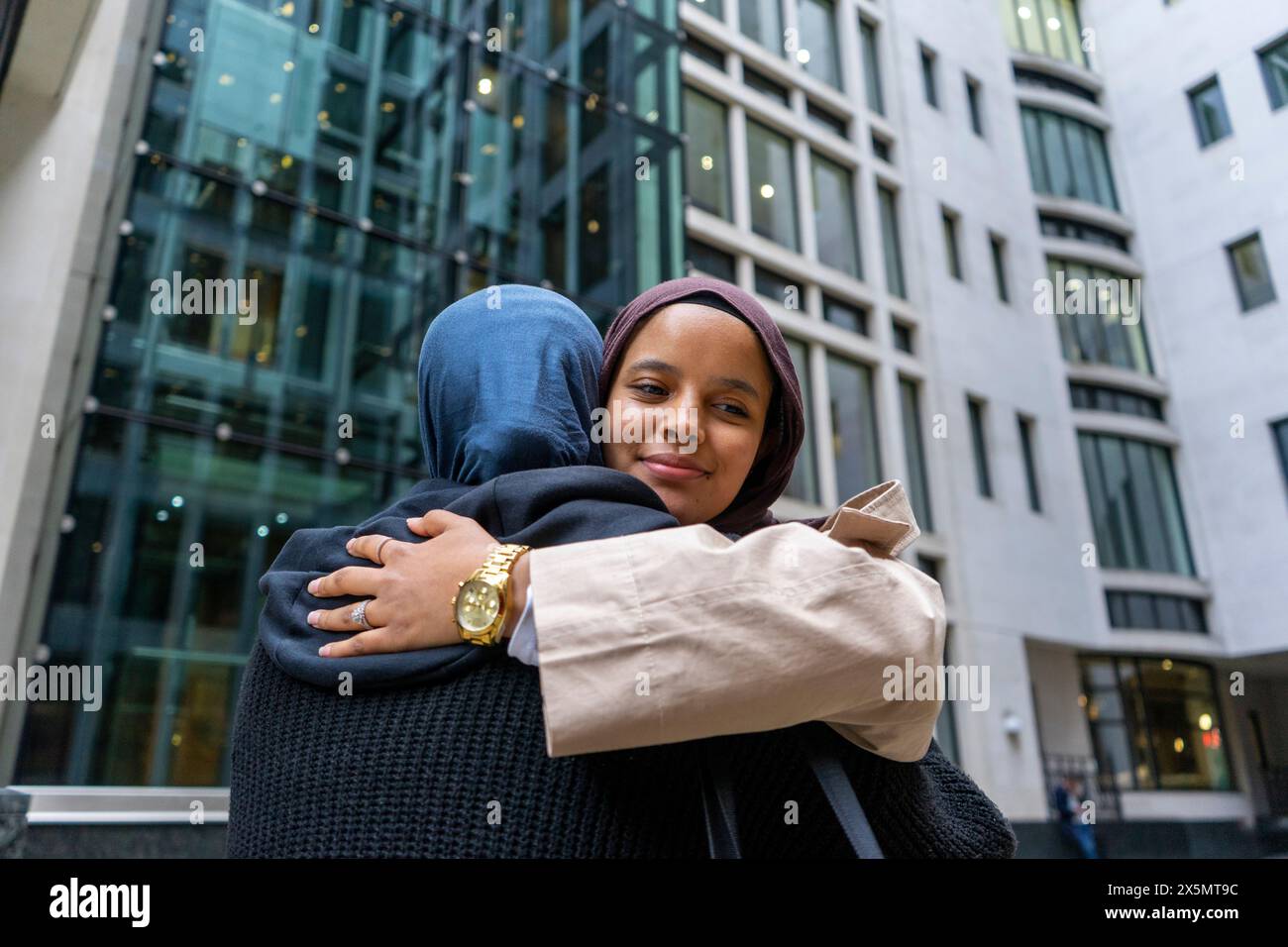 Two women wearing hijabs hugging in street Stock Photo - Alamy