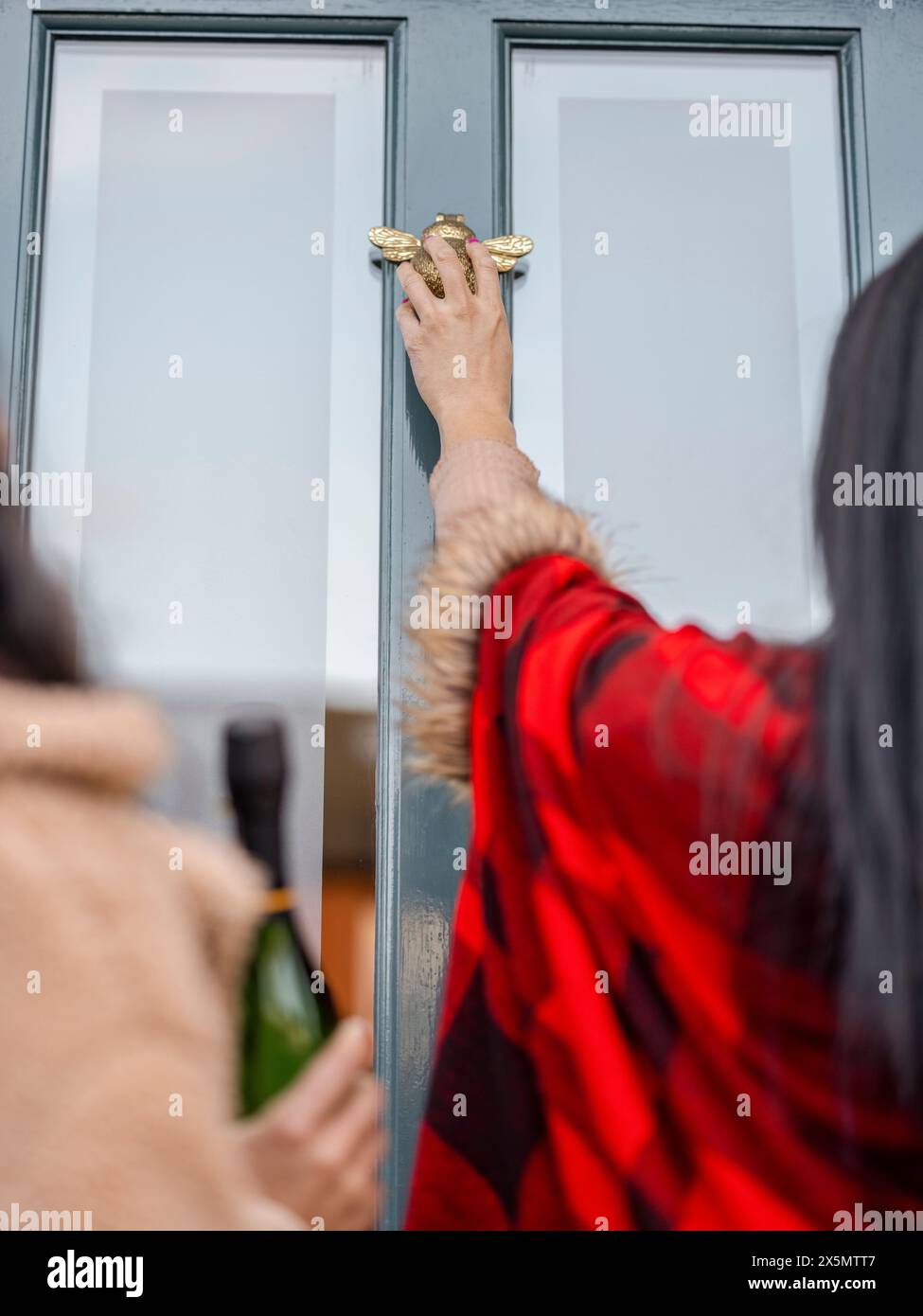 Female friends knocking house door Stock Photo - Alamy