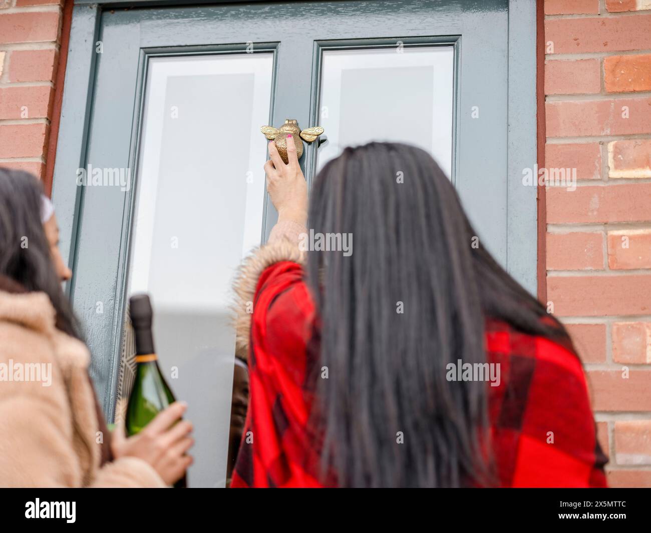 Female friends knocking house door Stock Photo - Alamy