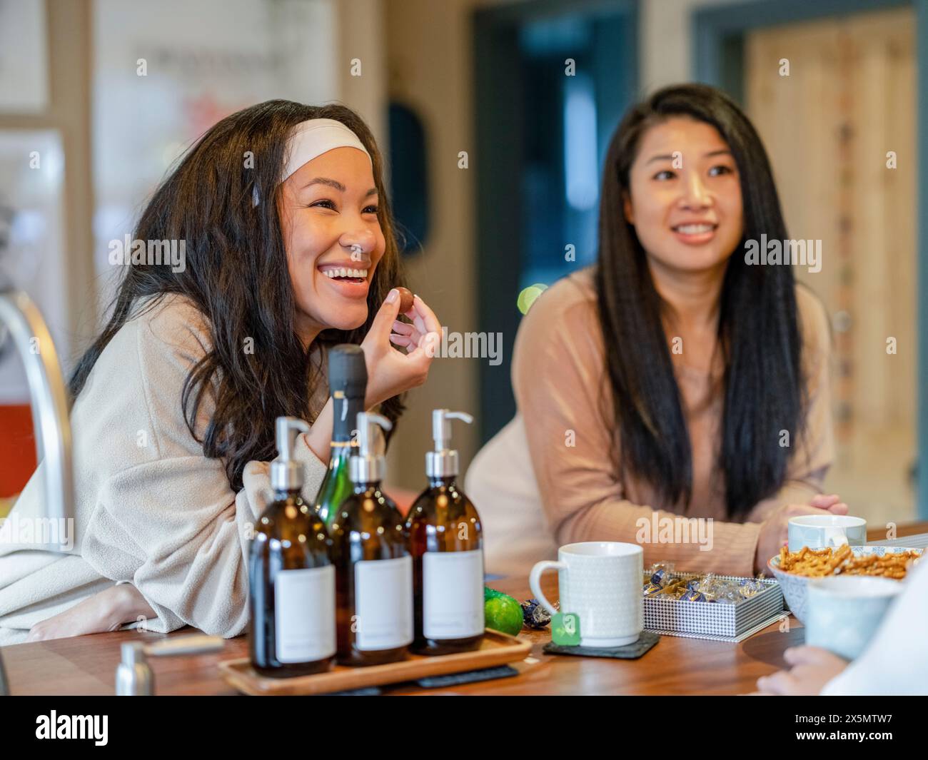 Female friends talking and eating in kitchen Stock Photo - Alamy