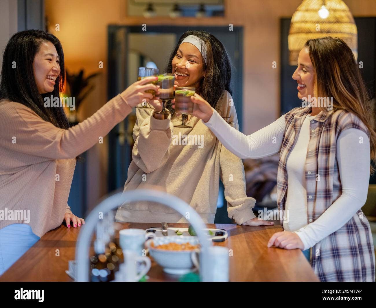 Female friends making celebratory toast in kitchen Stock Photo - Alamy