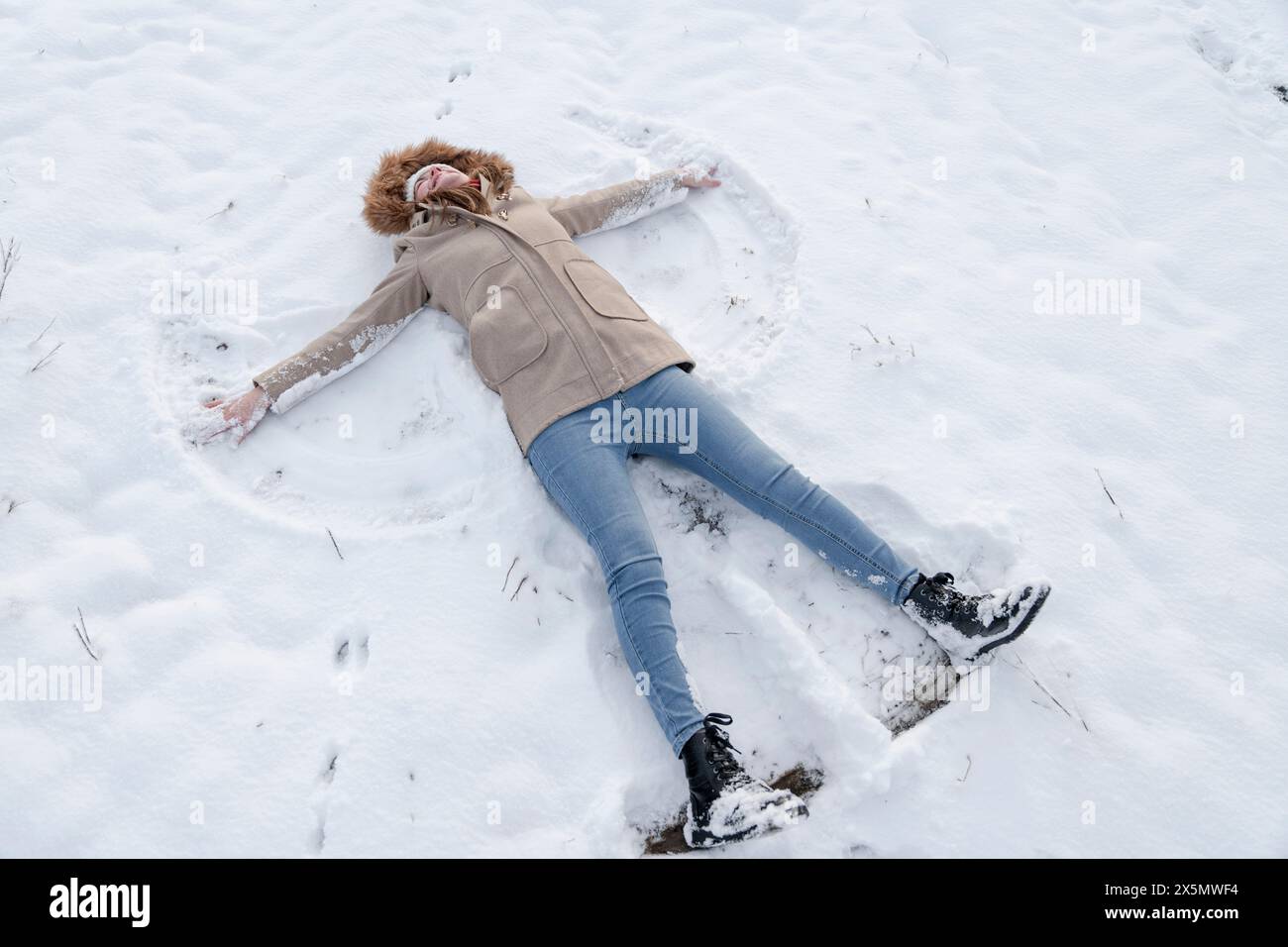 Woman making snow angel in winter landscape Stock Photo - Alamy
