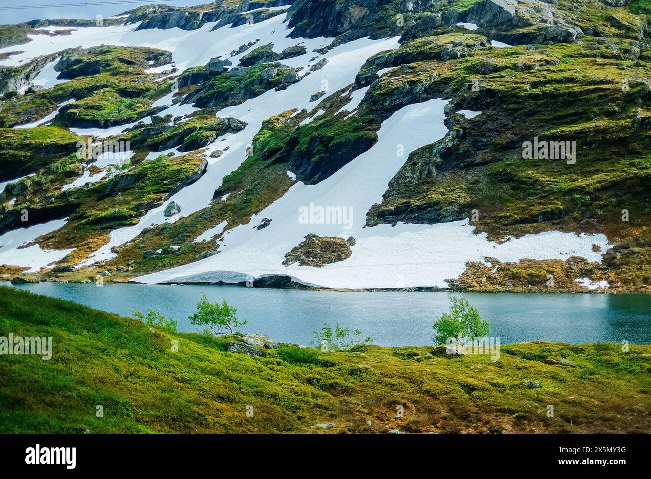 Snowcapped mountains hill and land next to blue lake in Norway Stock ...