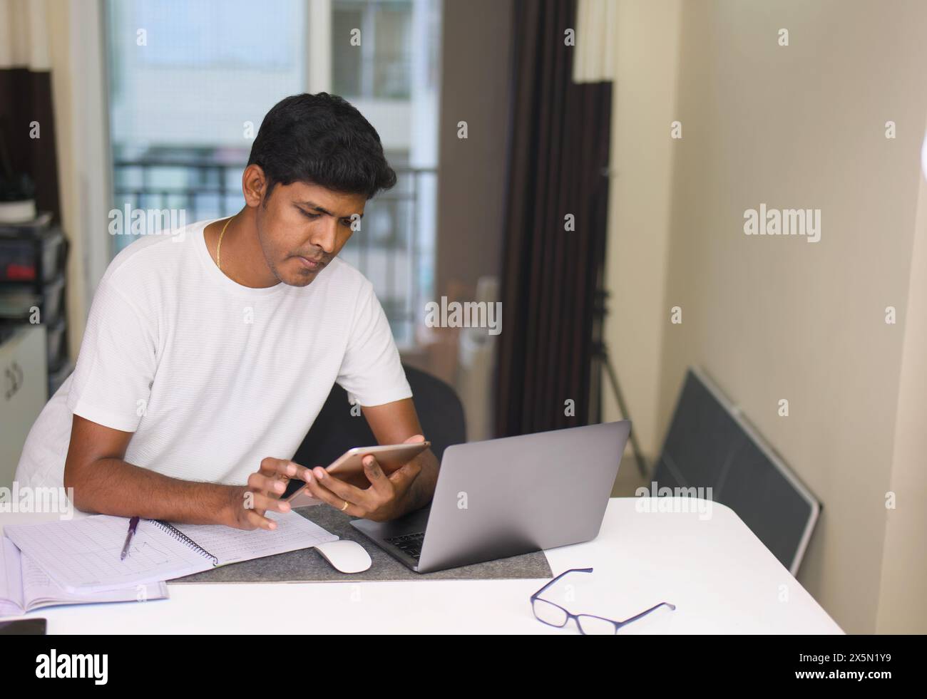 Concentrated young Indian man wearing headphones using laptop computer ...