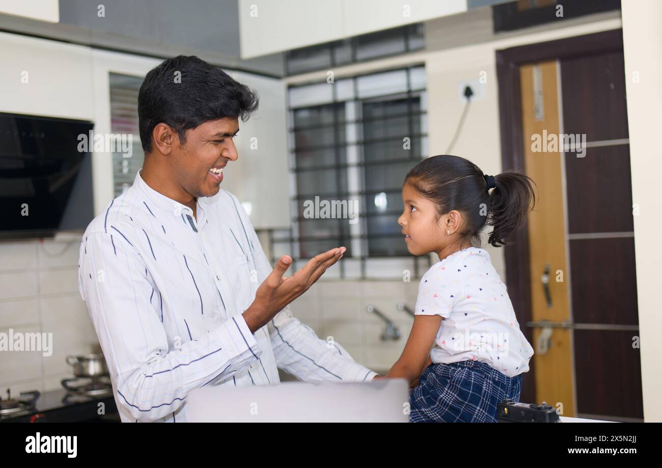 A bright-eyed girl sits captivated by a laptop screen in the kitchen ...