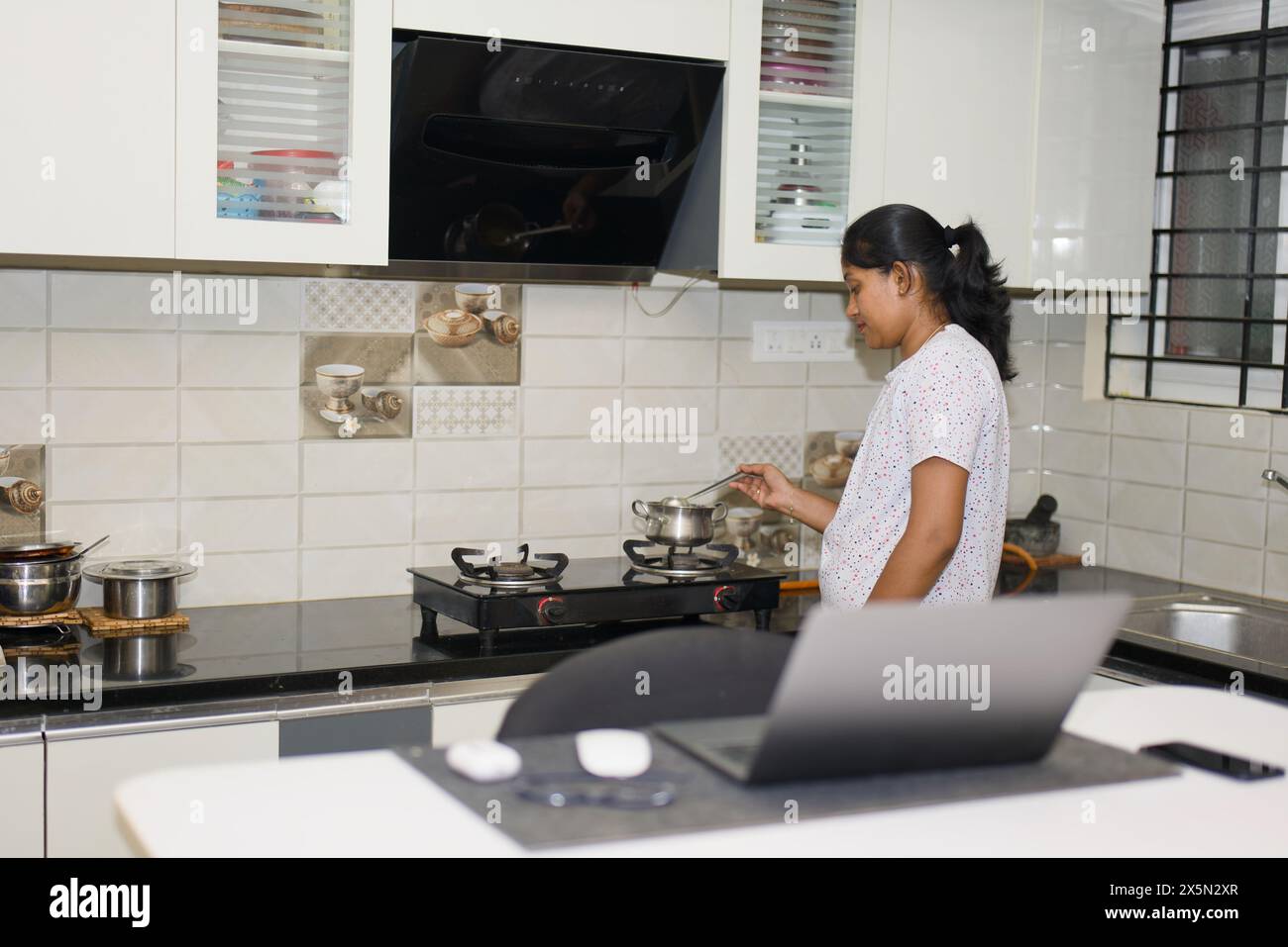 A focused young woman efficiently cooks a meal in her kitchen while ...