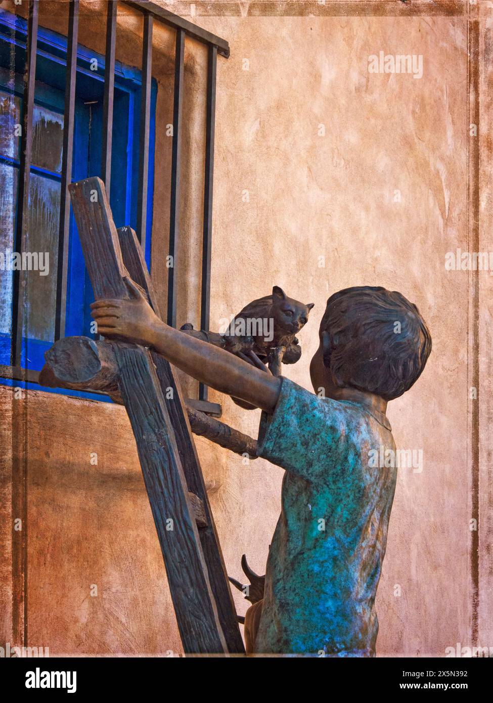 USA, New Mexico, Sante Fe. Colorful bronze statue of a boy on a ladder ...