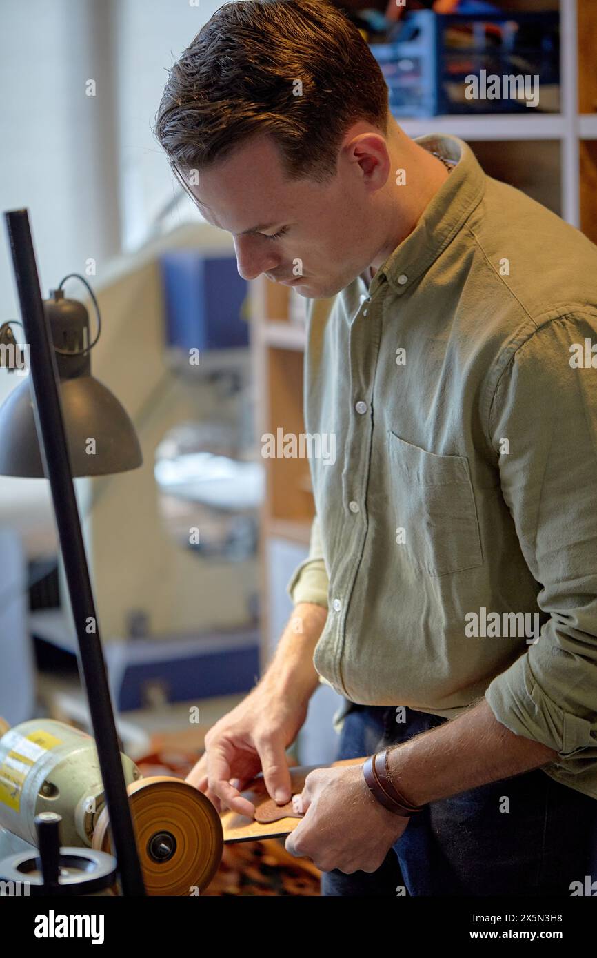 skilled artisan concentrated on using burnishing machine, close up side ...