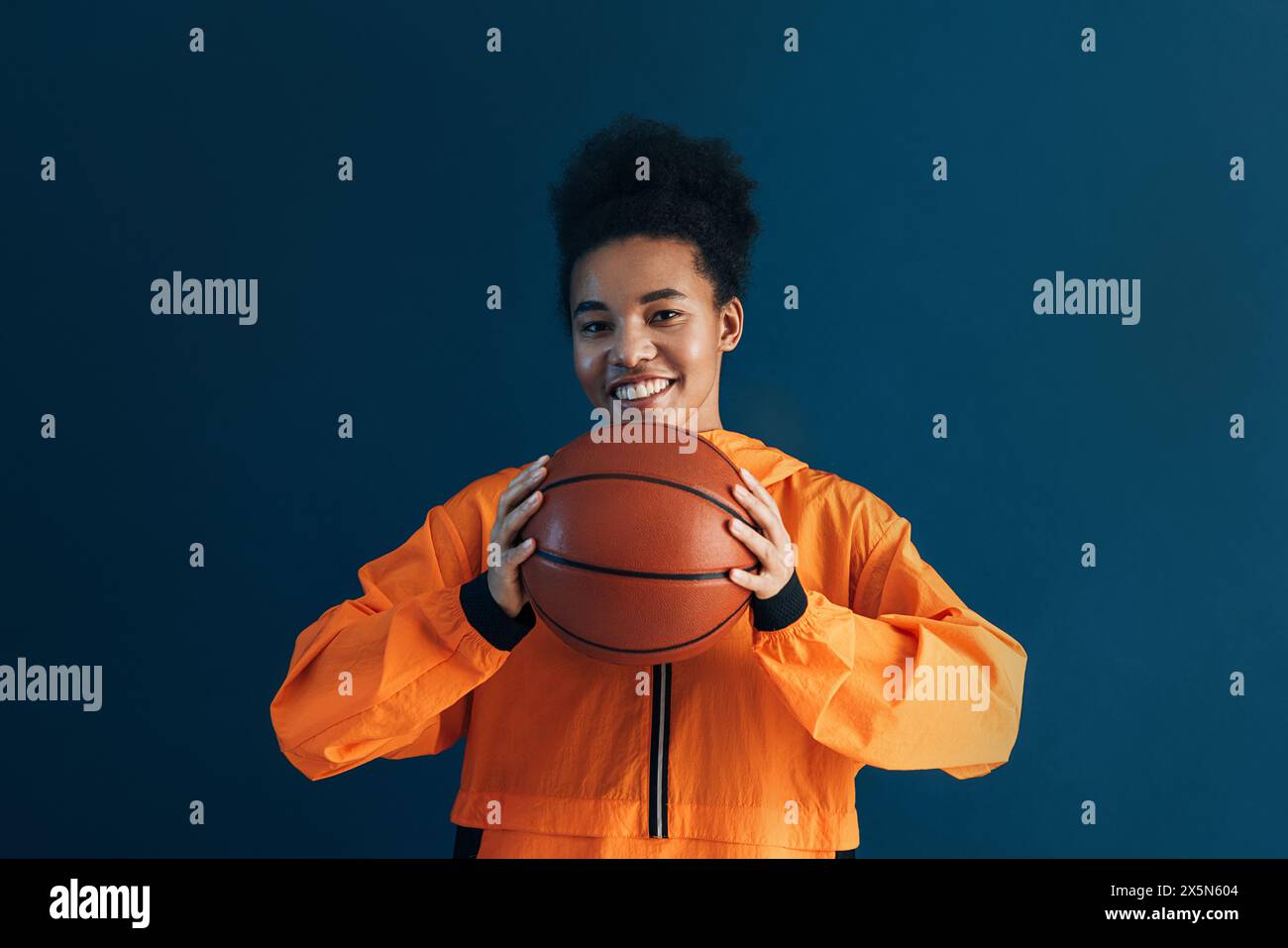 Happy basketball player with a ball over the blue backdrop. Smiling ...