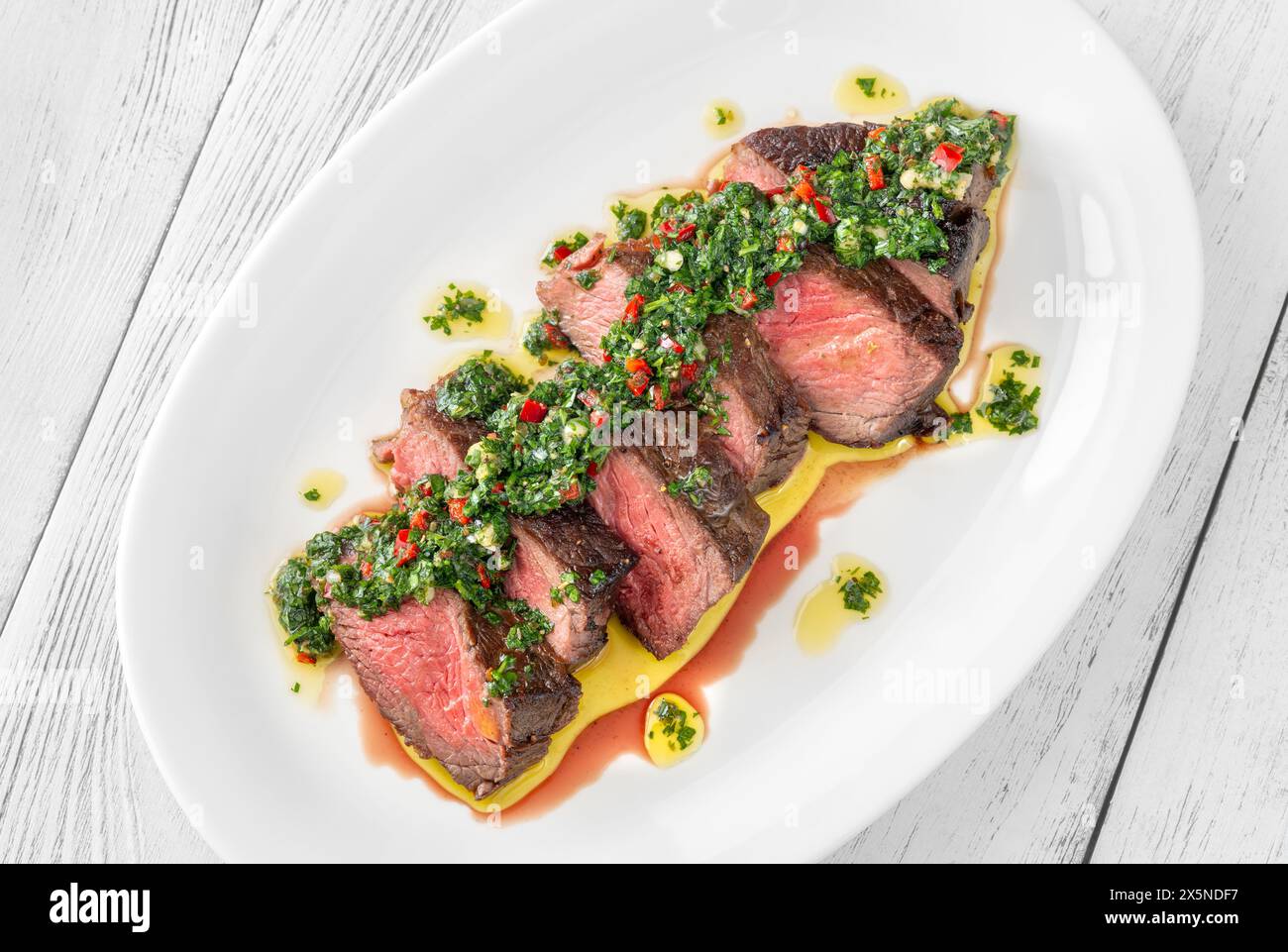 Portion of sliced strip steak with Chimichurri sauce Stock Photo - Alamy
