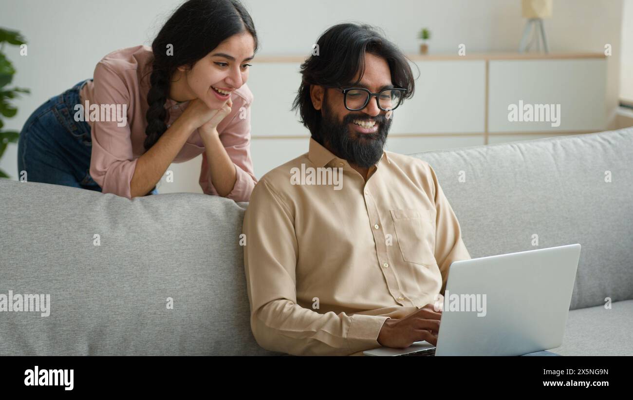 Arabian Indian couple on couch sofa use computer laptop shopping online ...