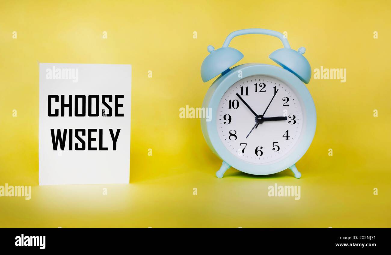 Text CHOOSE WISELY on a notepad on a light background table with a ...
