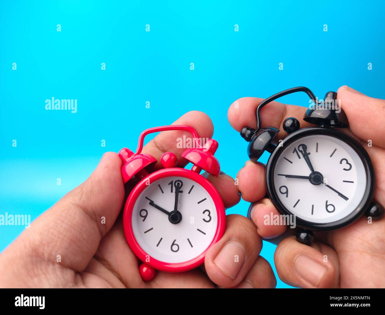 Hand holding alarm clock on a blue background with copy space Stock ...