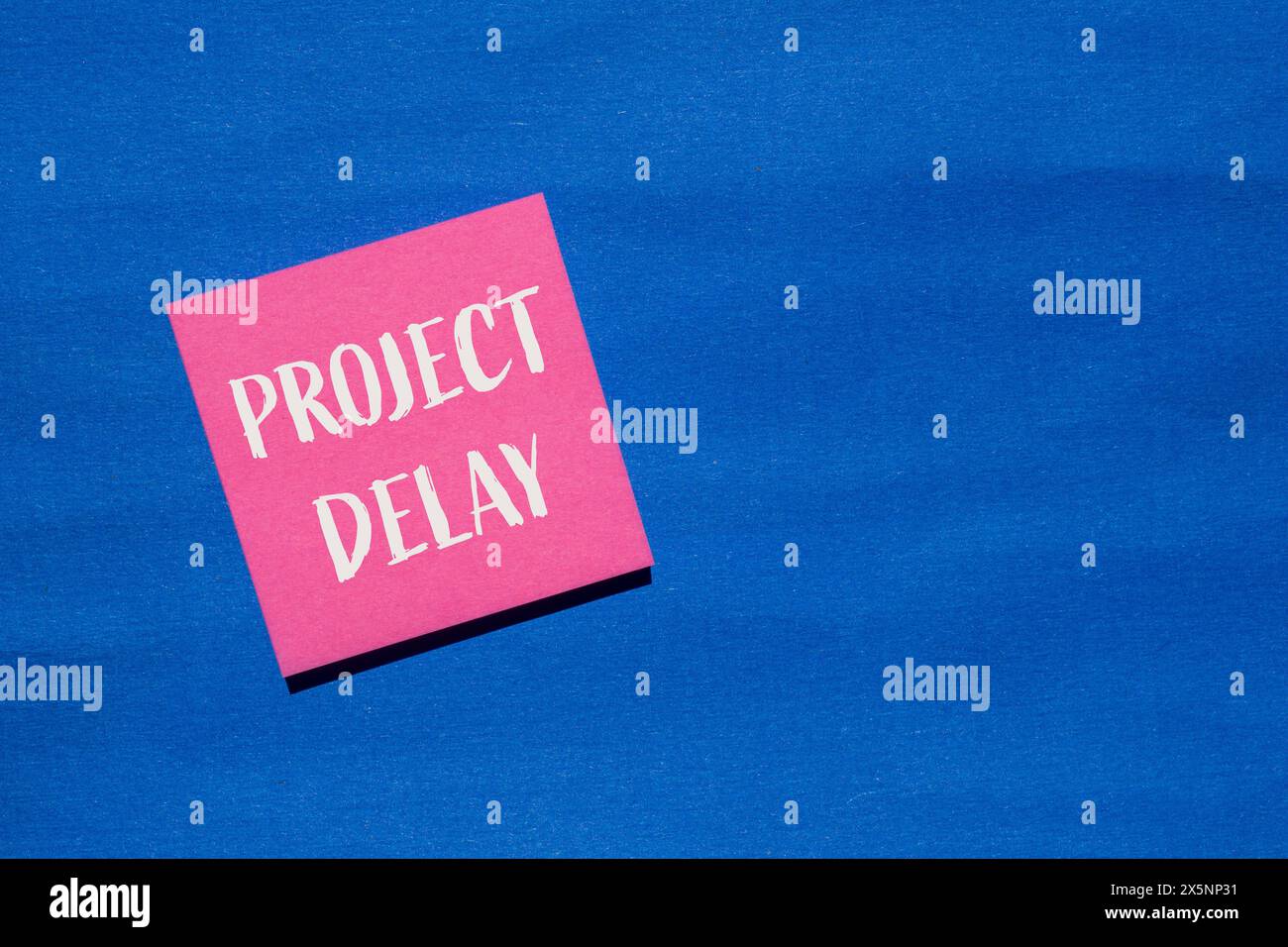 Project delay words written on pink paper sticker with blue background ...
