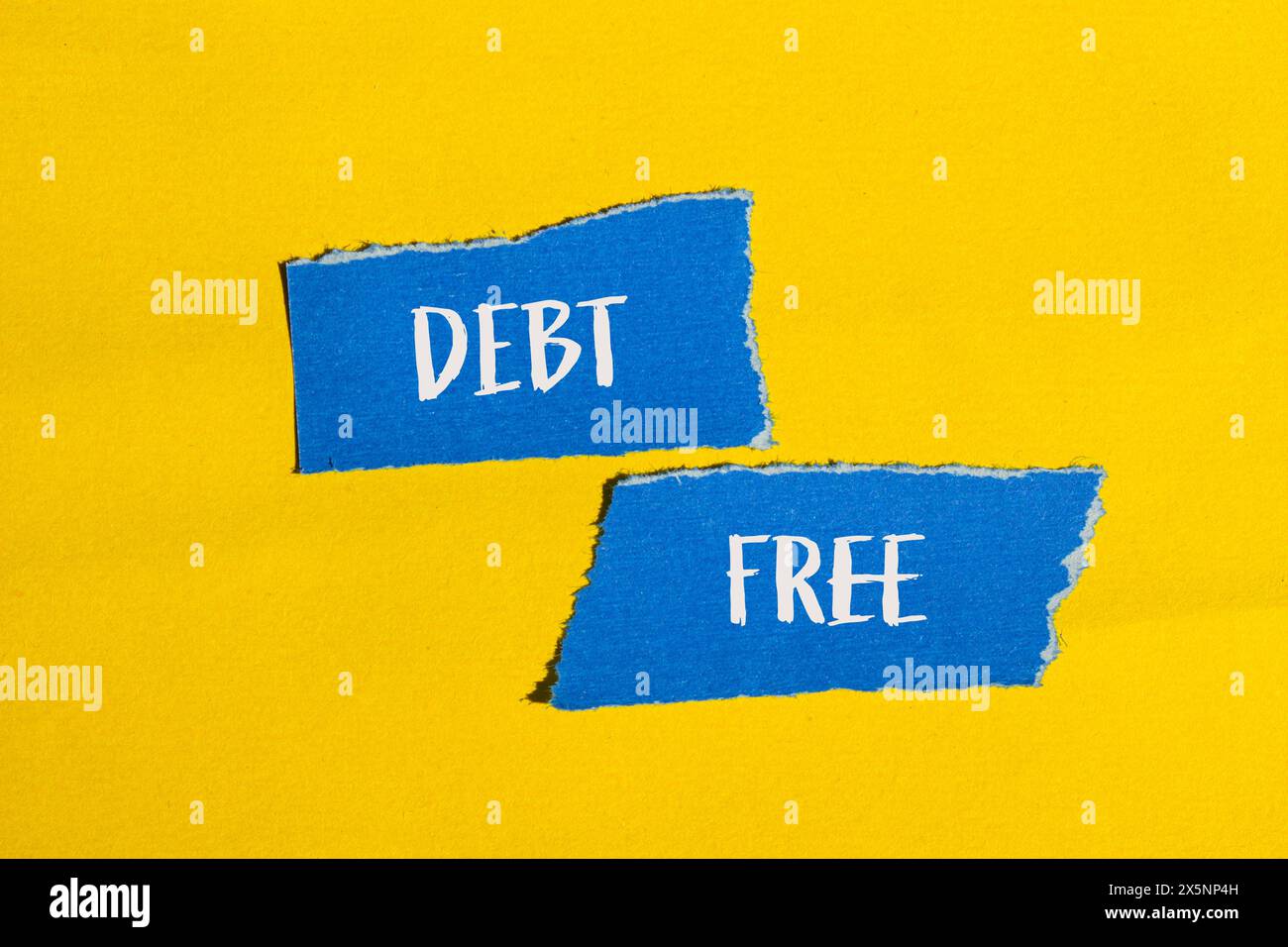 Debt free words written on ripped blue paper pieces with yellow ...